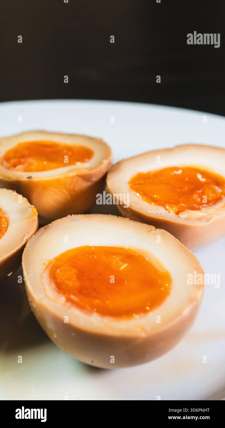 Four perfectly sliced ajitsuke tamago eggs on a plate, showing creamy ...