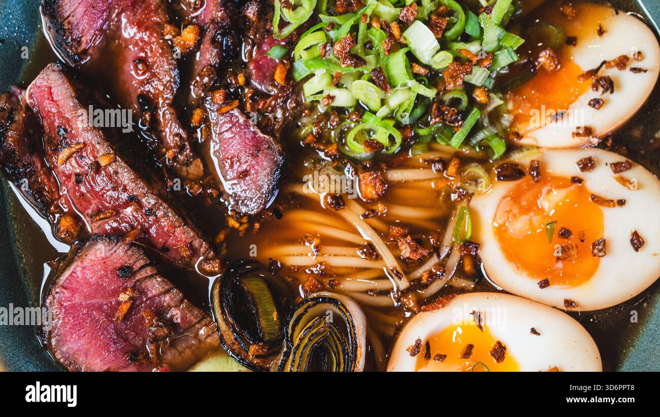 Savory beef ramen with rare steak slices, spring onions, bamboo shoots ...
