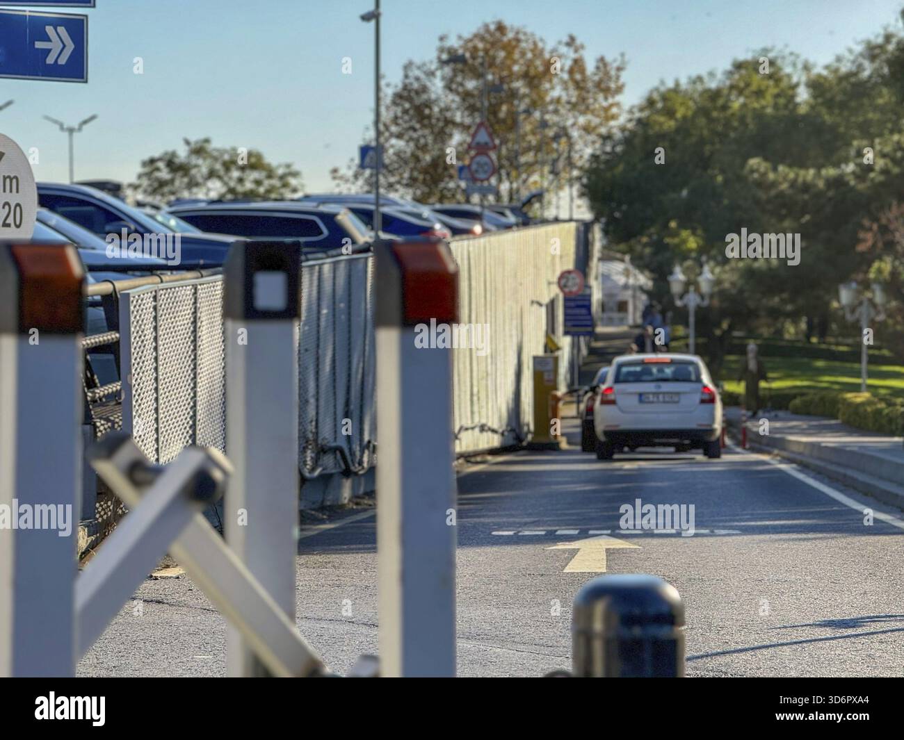 A white car waits at an exit barrier of a parking and restricted area ...