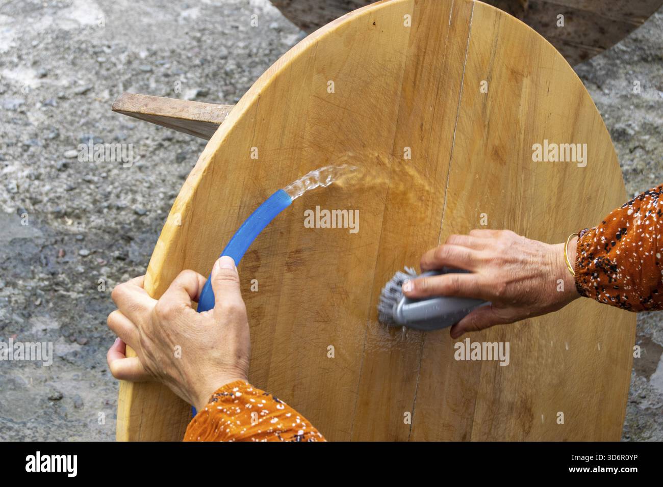 A woman cleans the round wooden Saj table, traditionally used for ...