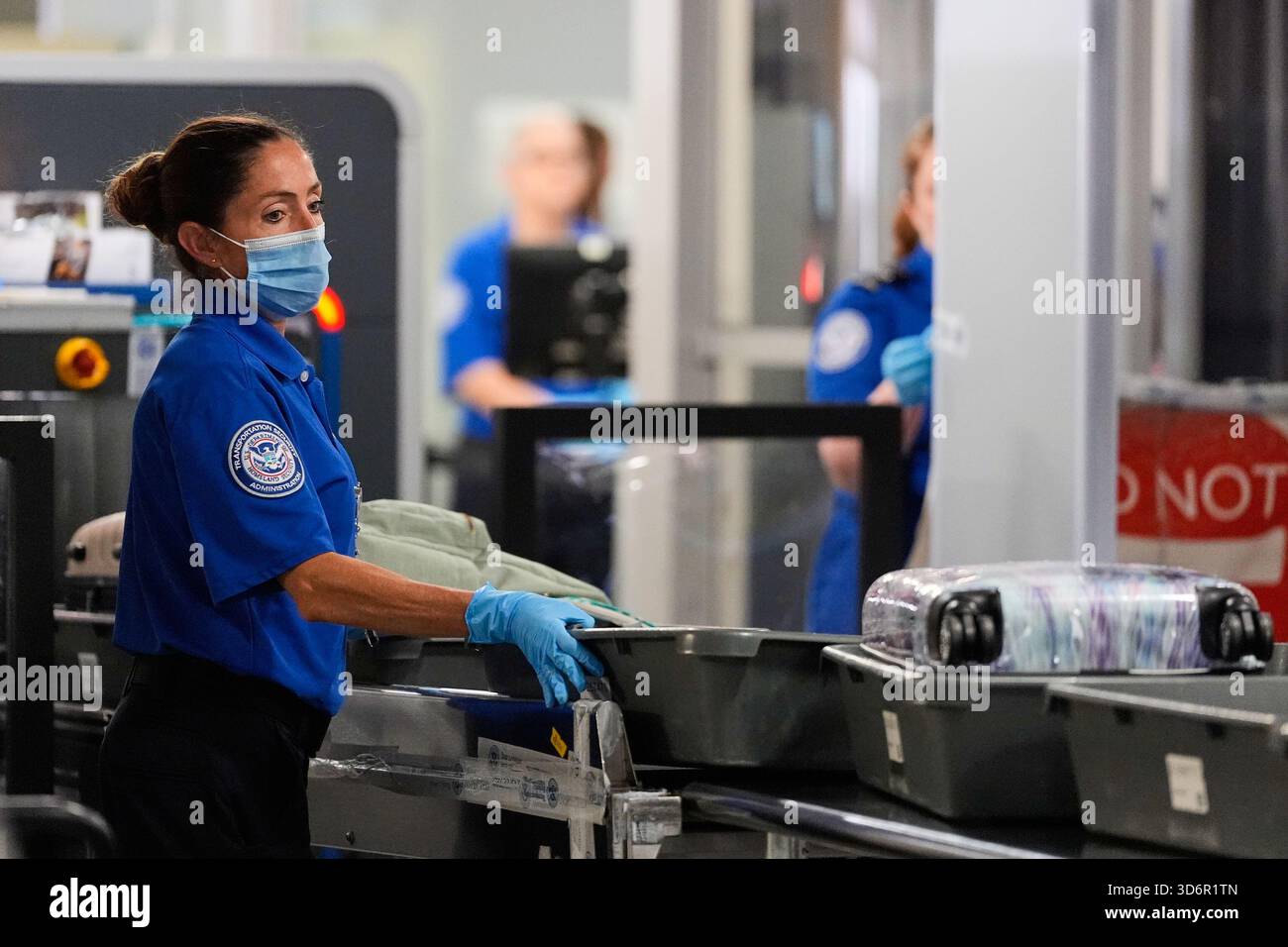 A TSA agent pushes bins along at a security checkpoint at the Dallas ...