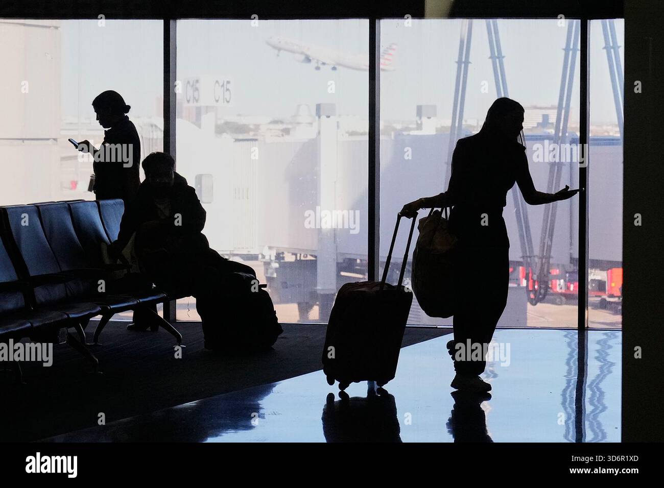 Travelers wait at a gate for their departing flight at the Dallas Fort ...