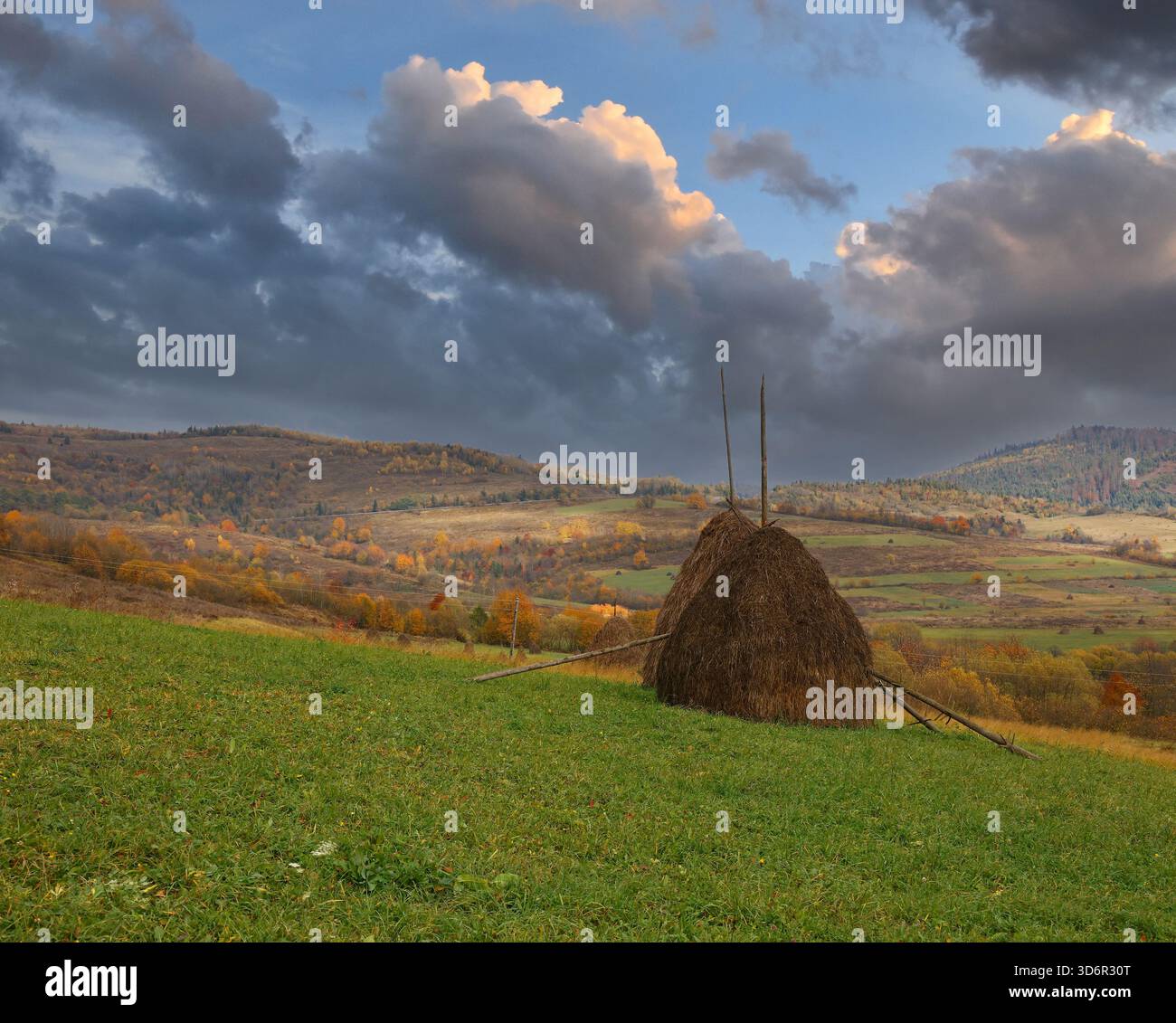 Haystack on a green meadow beneath a moody autumn sky, overlooking a ...