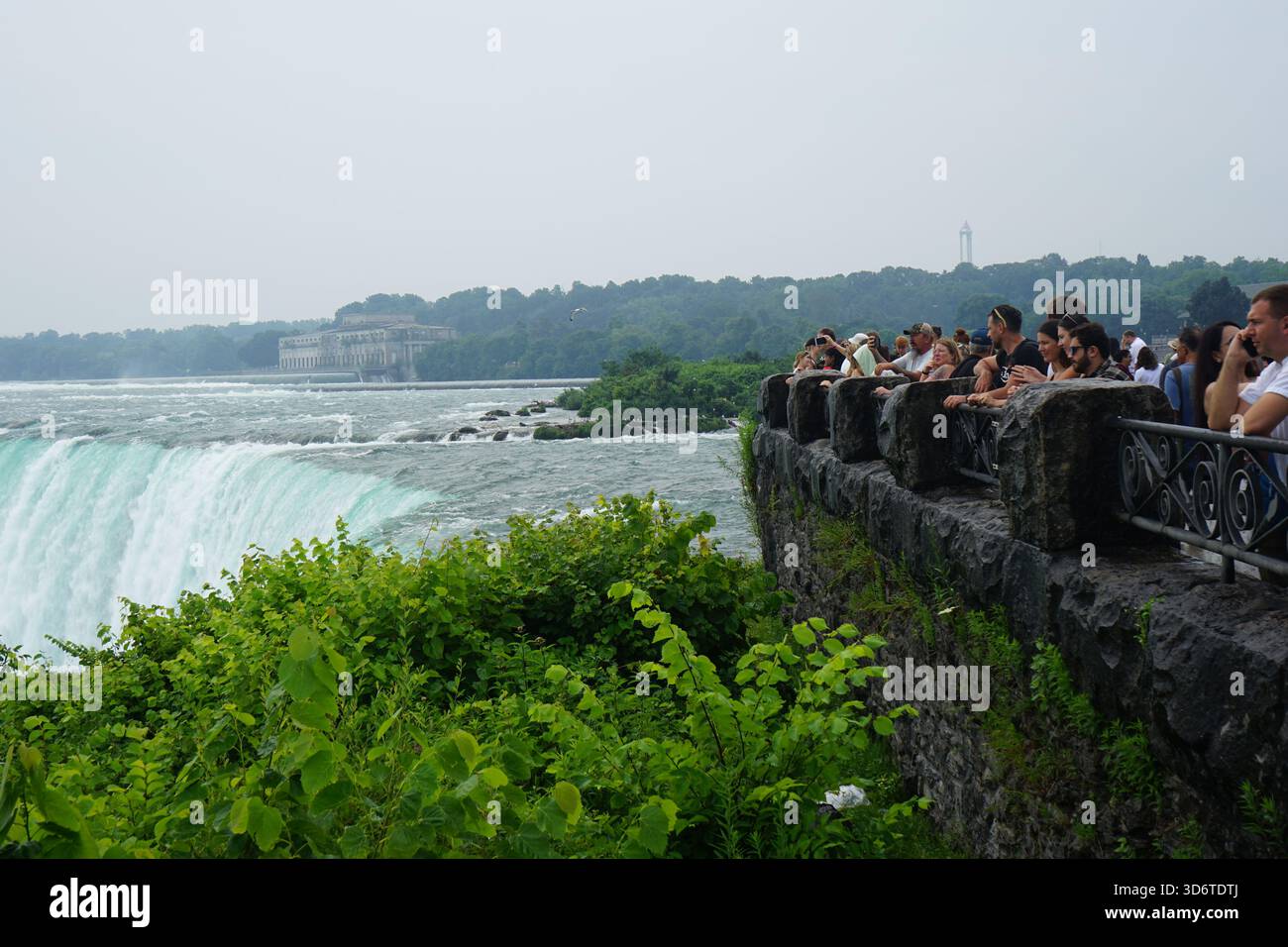 Crowd of tourists watch water tumbling over the top of Horseshoe Falls ...
