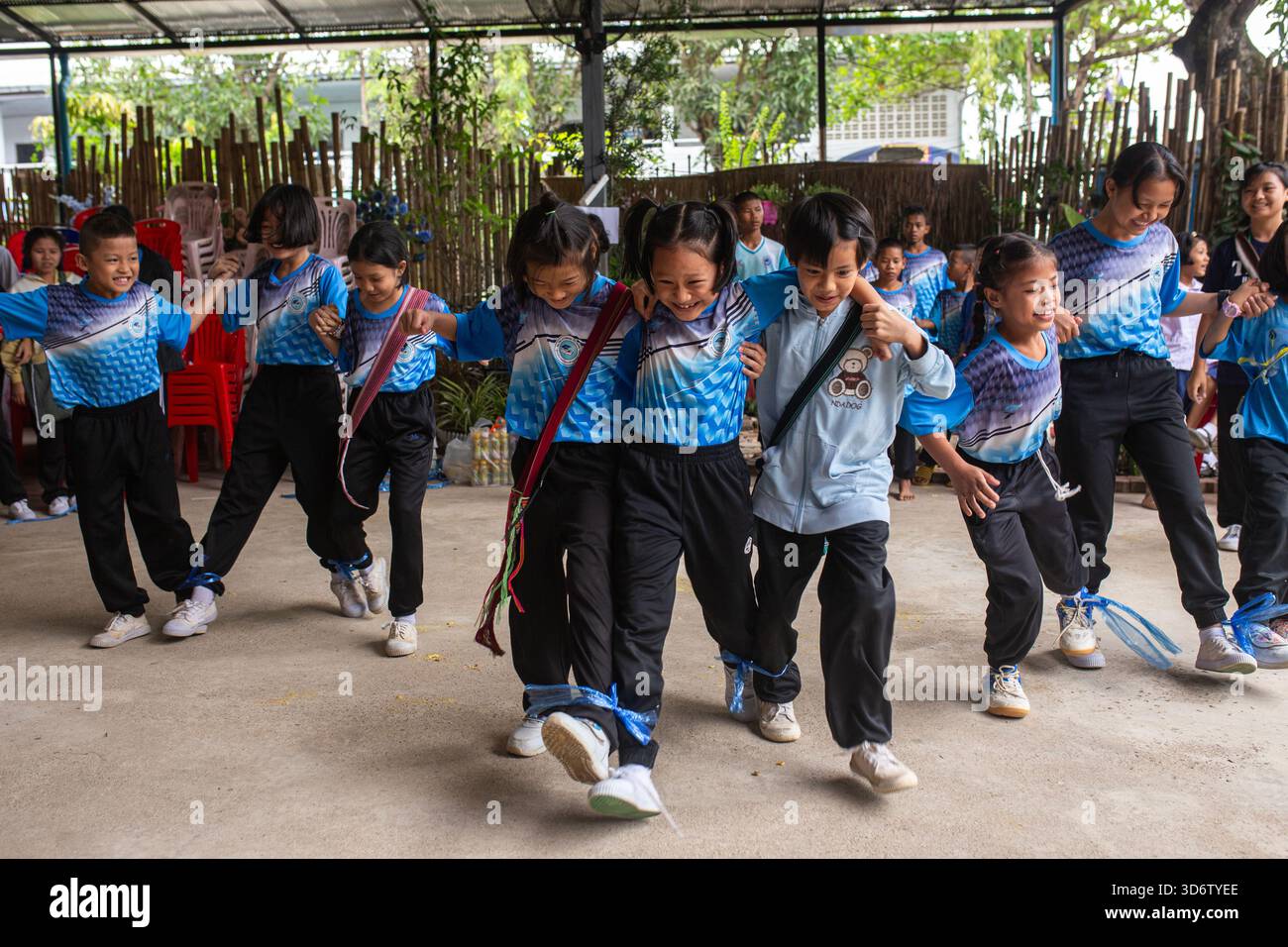 Migrant students play a game where their legs are tied together while ...