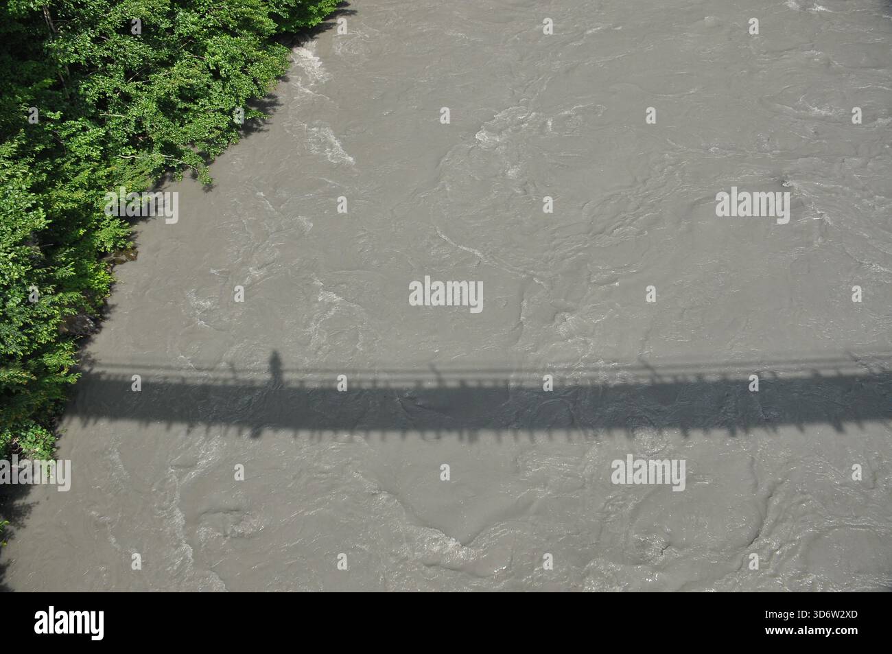 A long, dark shadow from a bridge stretches across the surface of a ...