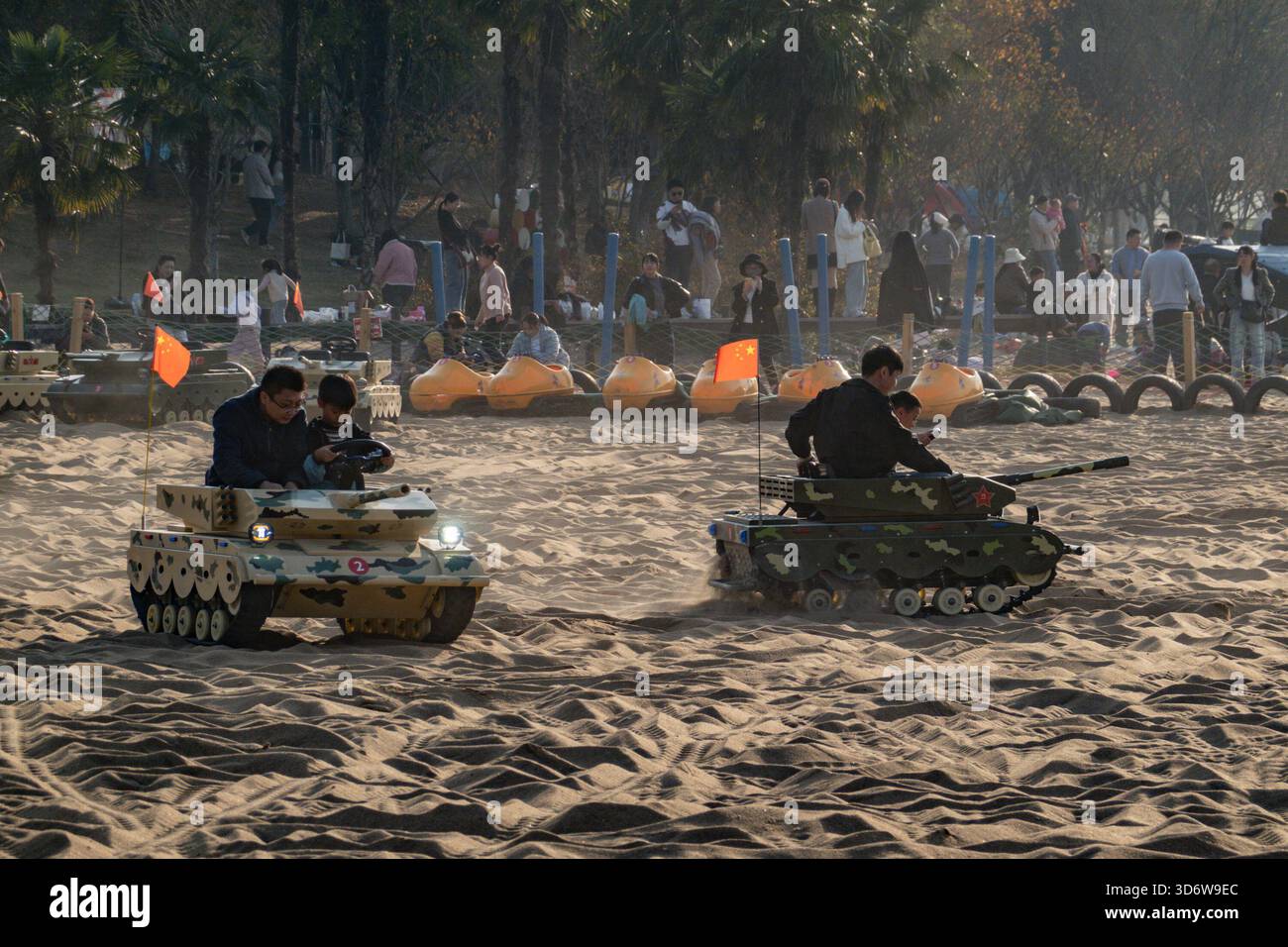 People drive toy tanks on the sand in the ecological park. (Photo by ...