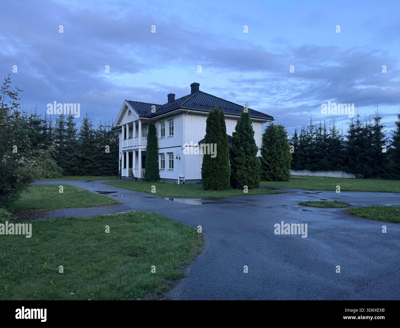 A white countryside house stands quietly at dusk, surrounded by tall ...