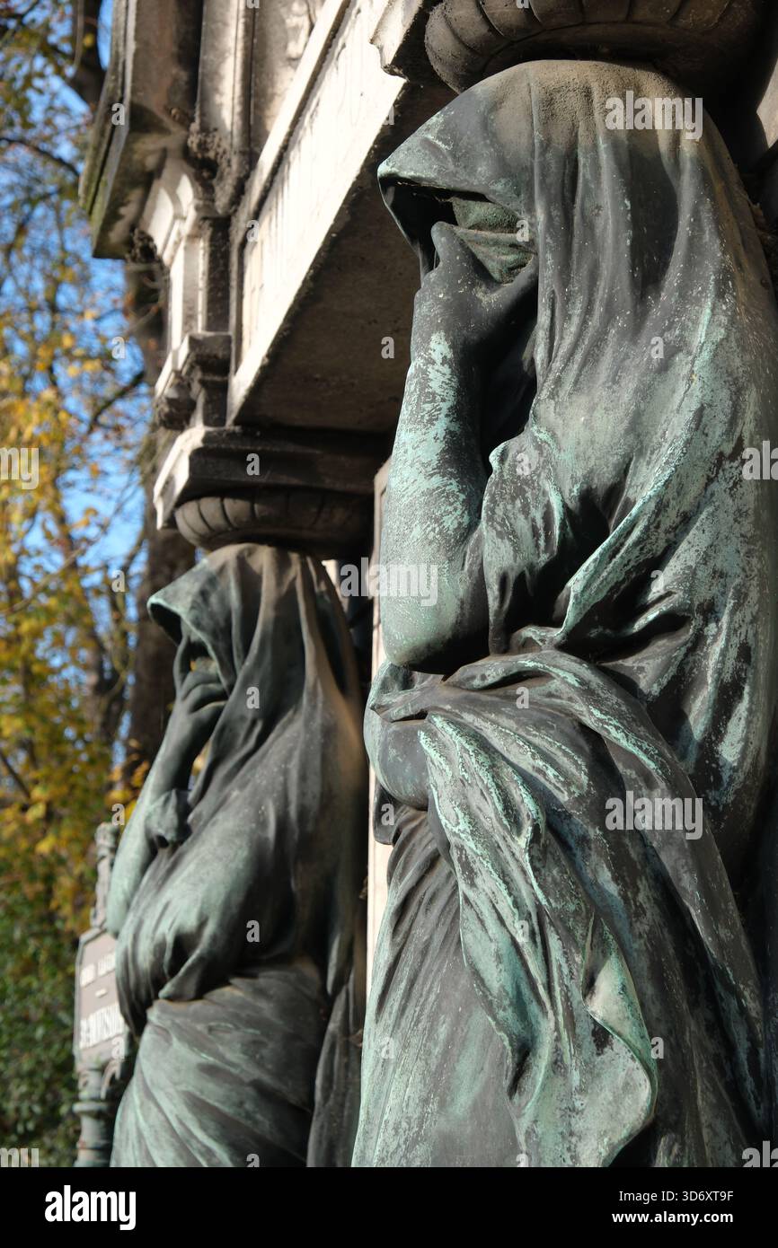 Two statues of people covering their face in mourning at Père Lachaise ...