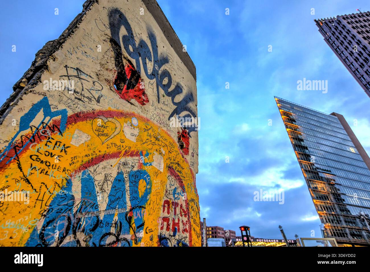 Graffiti-covered Berlin Wall slab with modern Potsdamer Platz ...