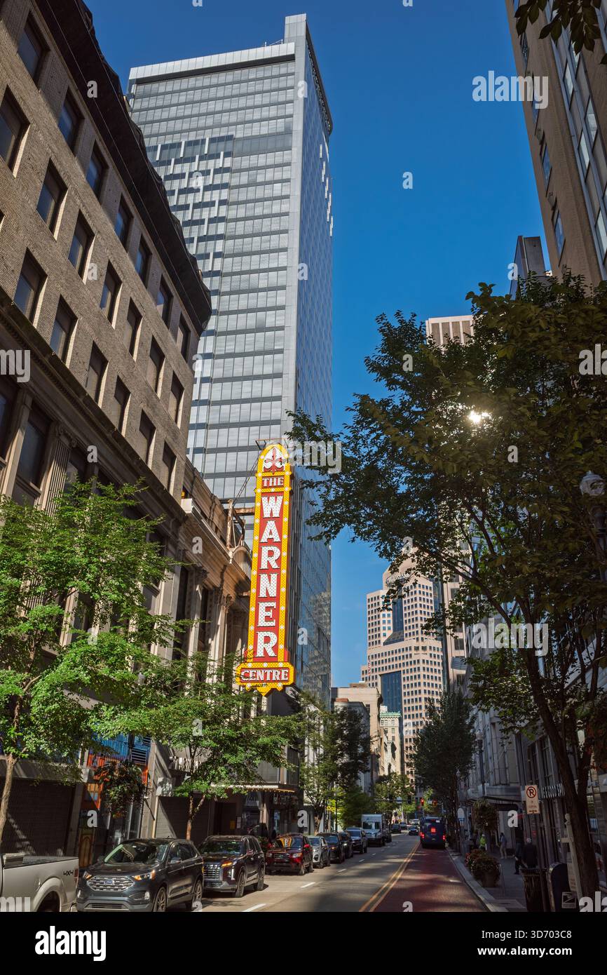 A vertical street view capturing the bright neon sign of The Warner ...