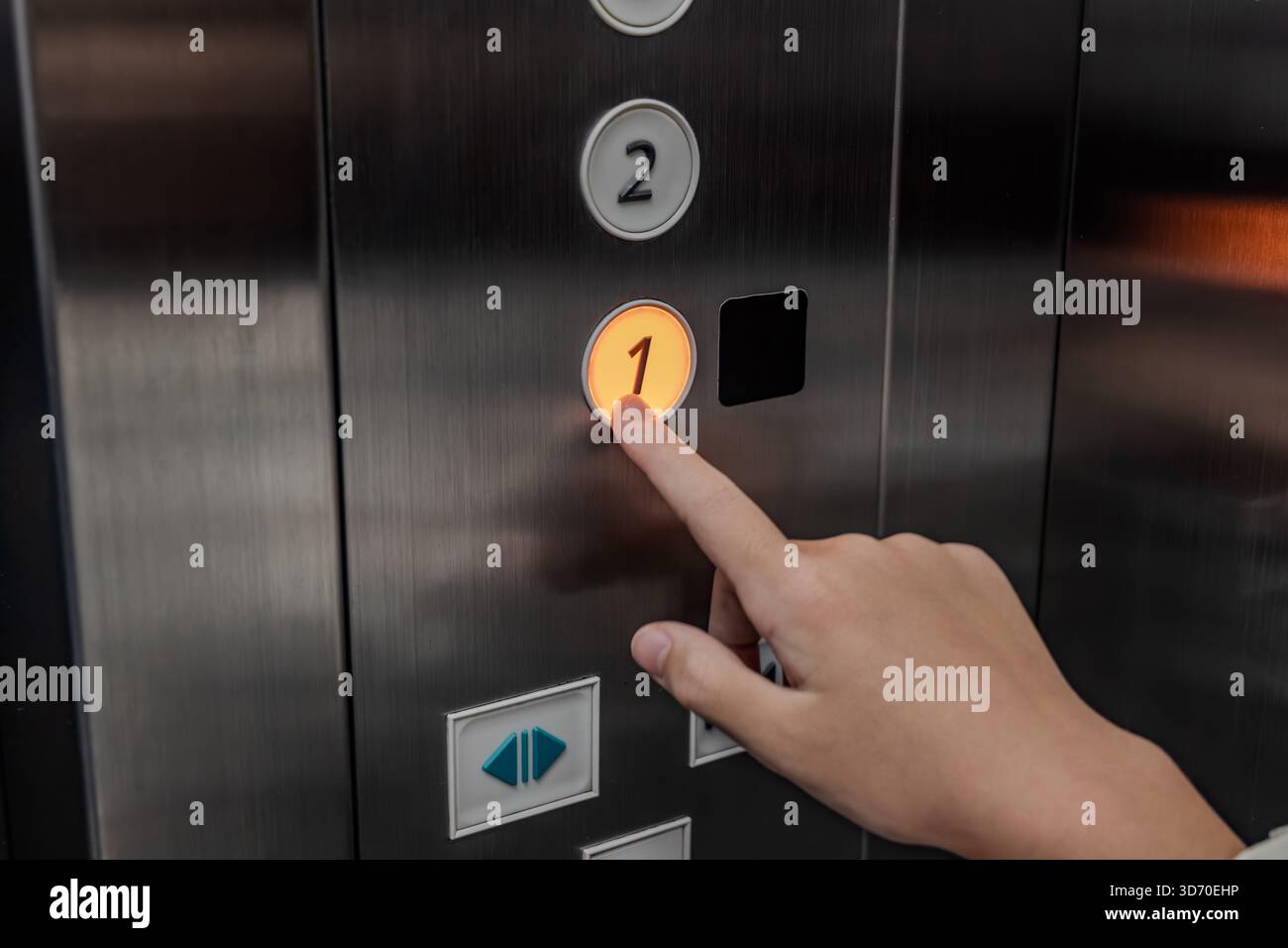 The hand of a girl kid presses an elevator button, showing a finger ...