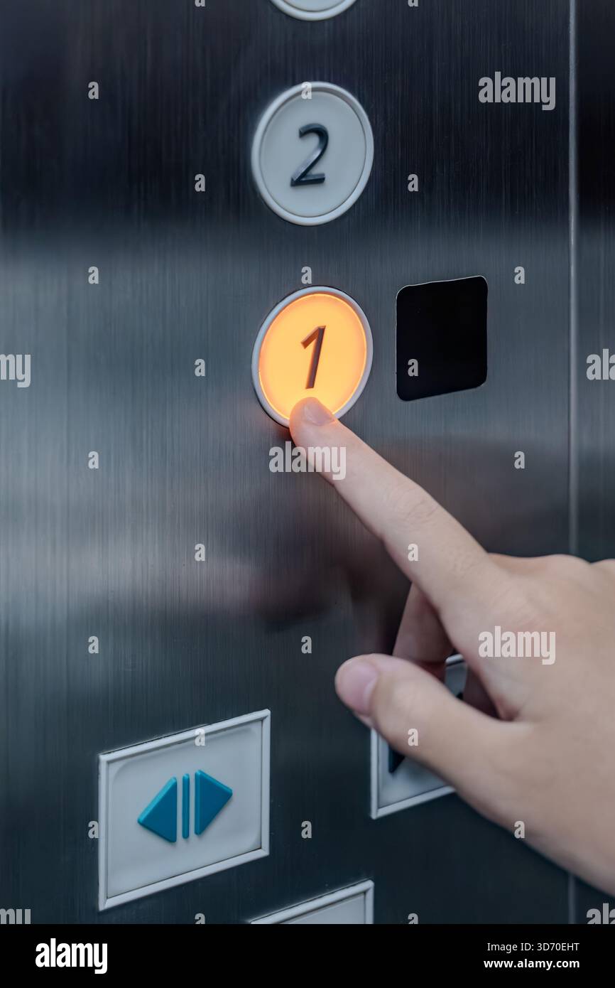 The hand of a girl kid presses an elevator button, showing a finger ...