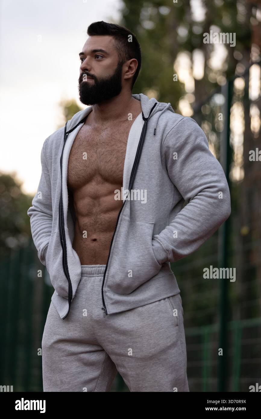 muscular man stands with a strong posture while wearing a gray athletic ...