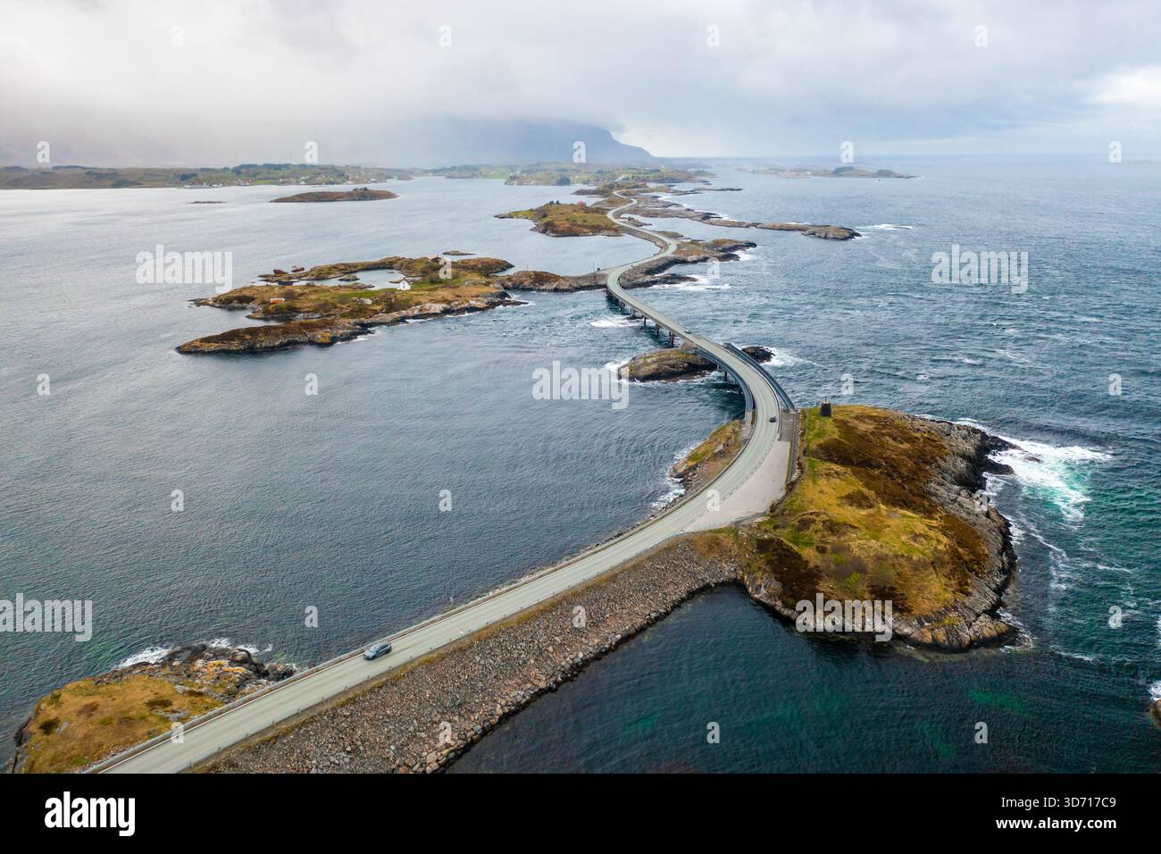 Cars drive on Atlantic ocean road with bridge connecting large islands ...