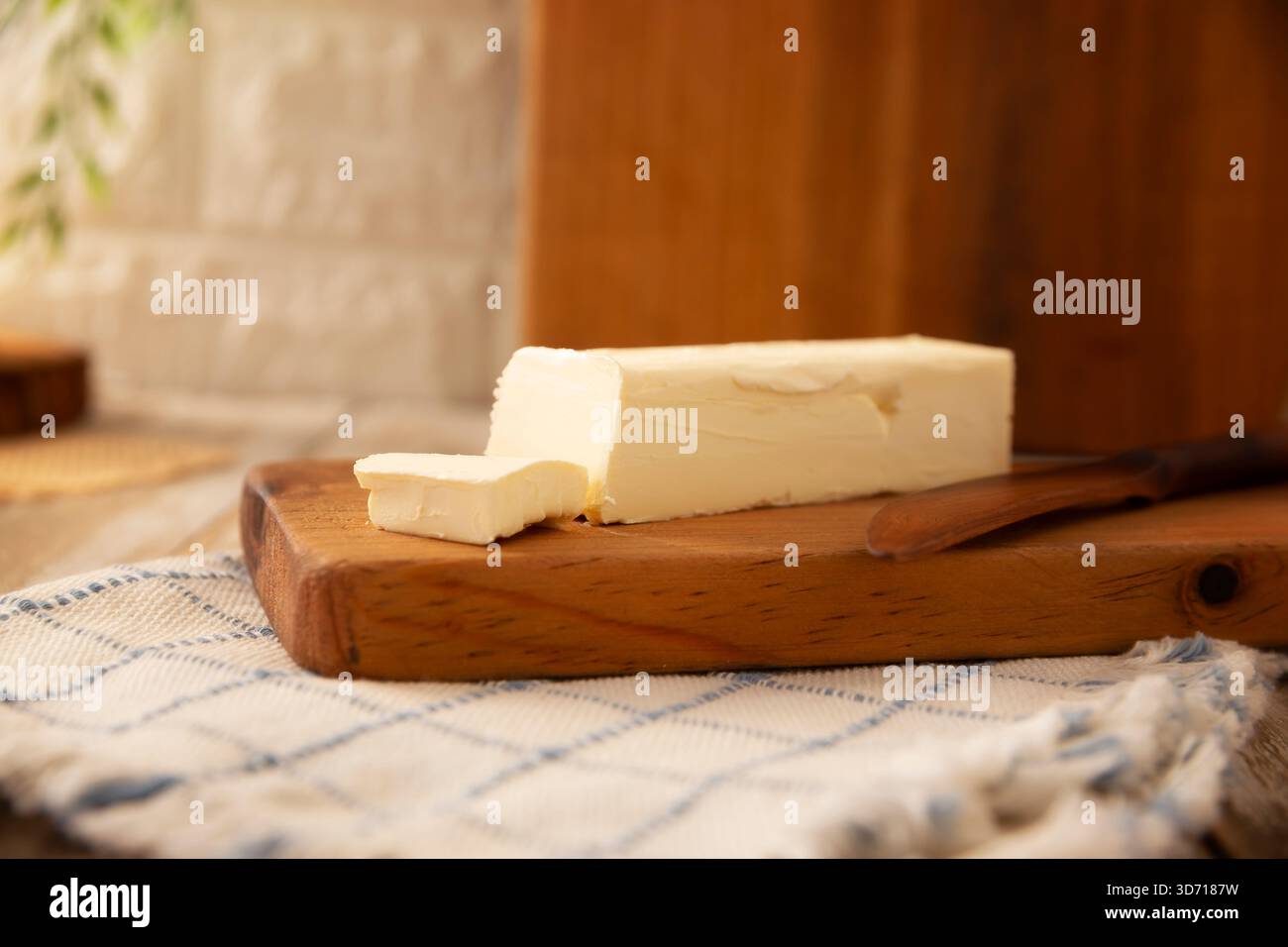 Stick of butter on a cutting board with a wooden knife. A common ...