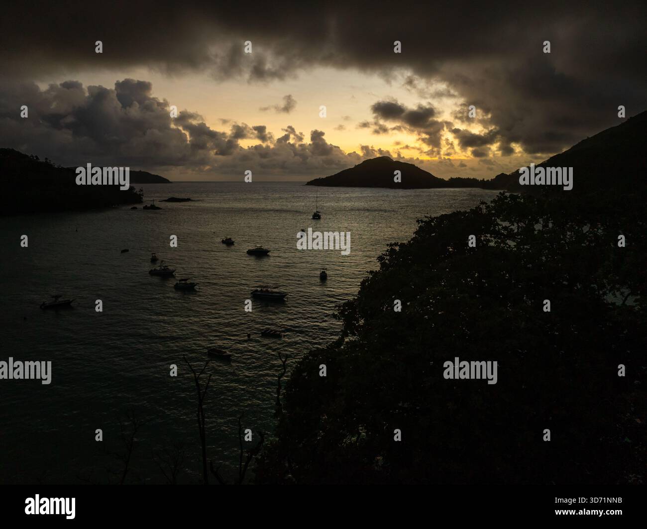 Multiple boats anchored in a calm bay at dusk with gentle waves and a ...