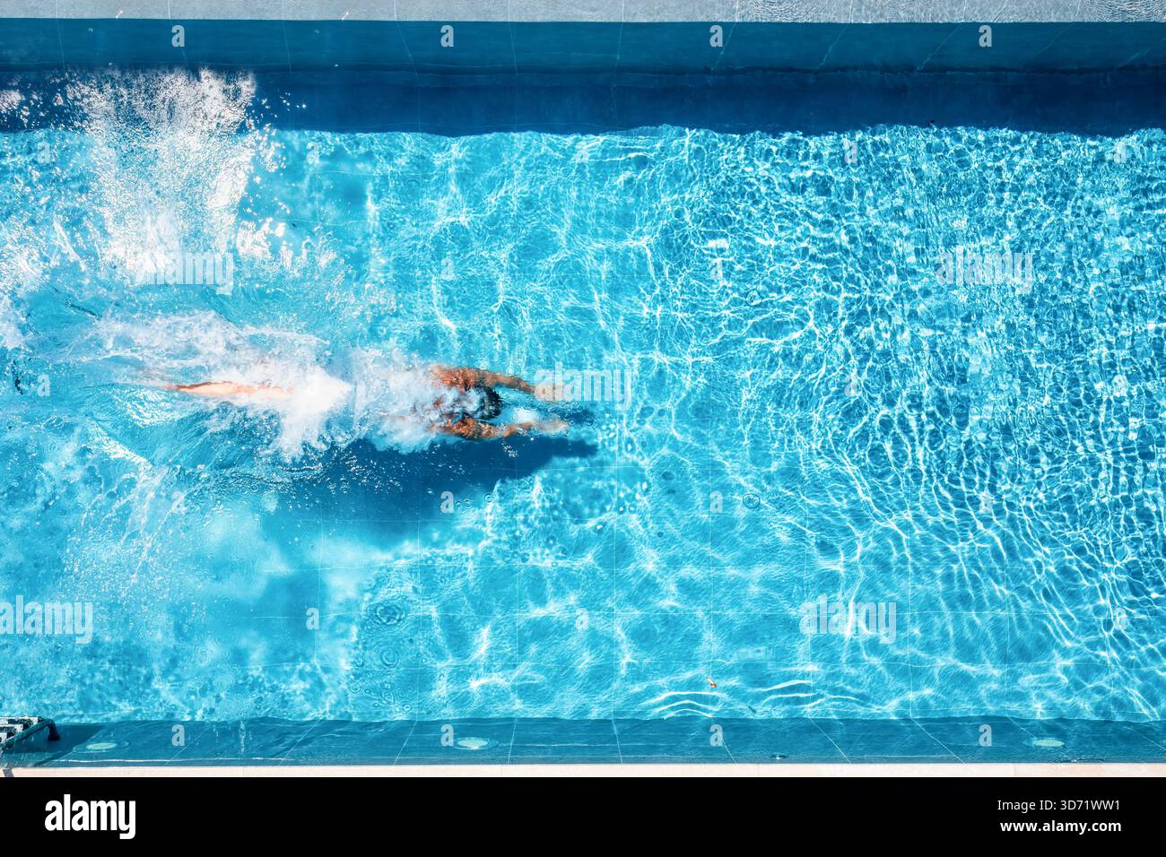 Aerial overhead view of a man jumping and diving into a swimming pool ...