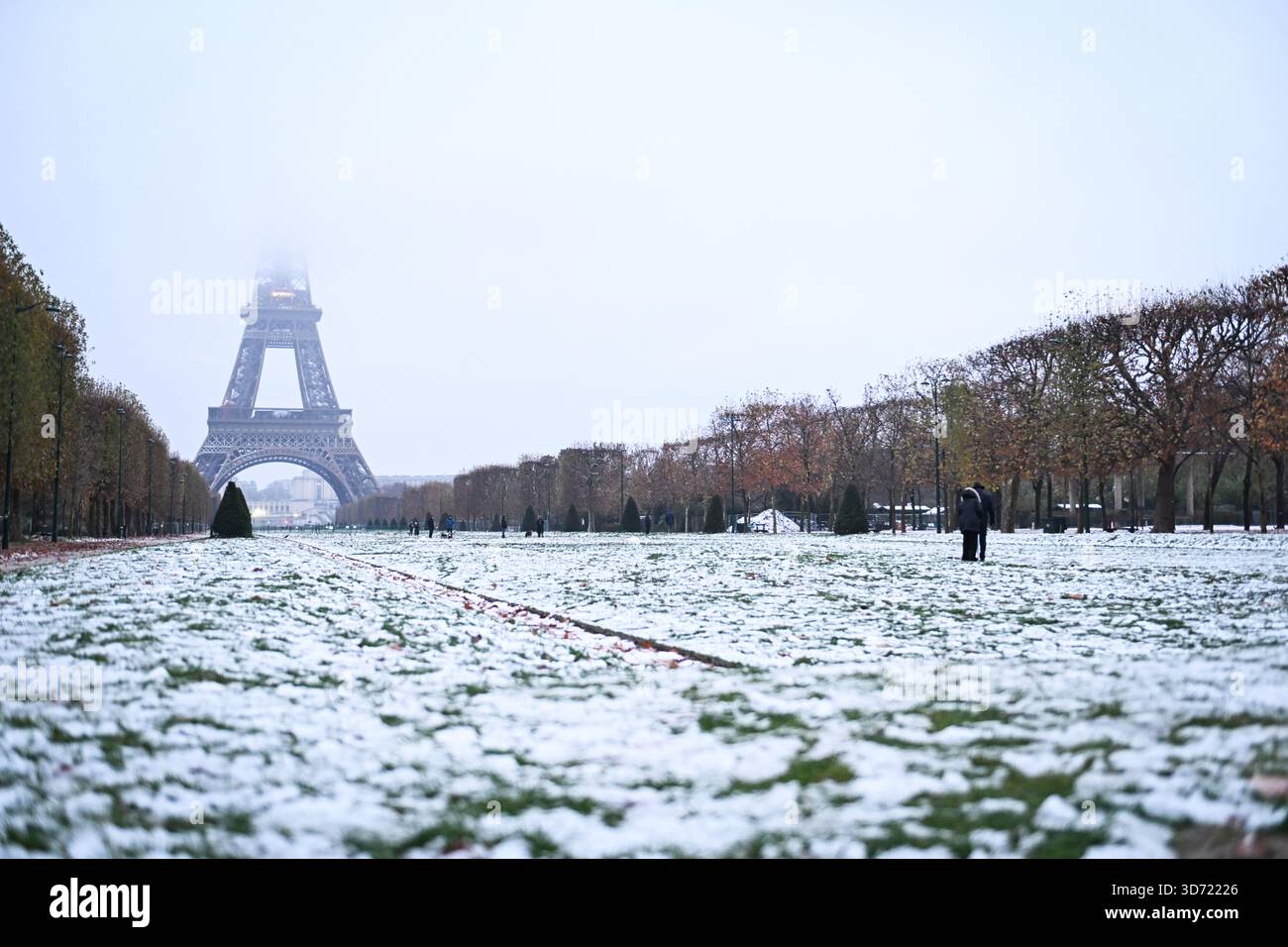 Pedestrians walk around as snow covers the ground around the Eiffel ...
