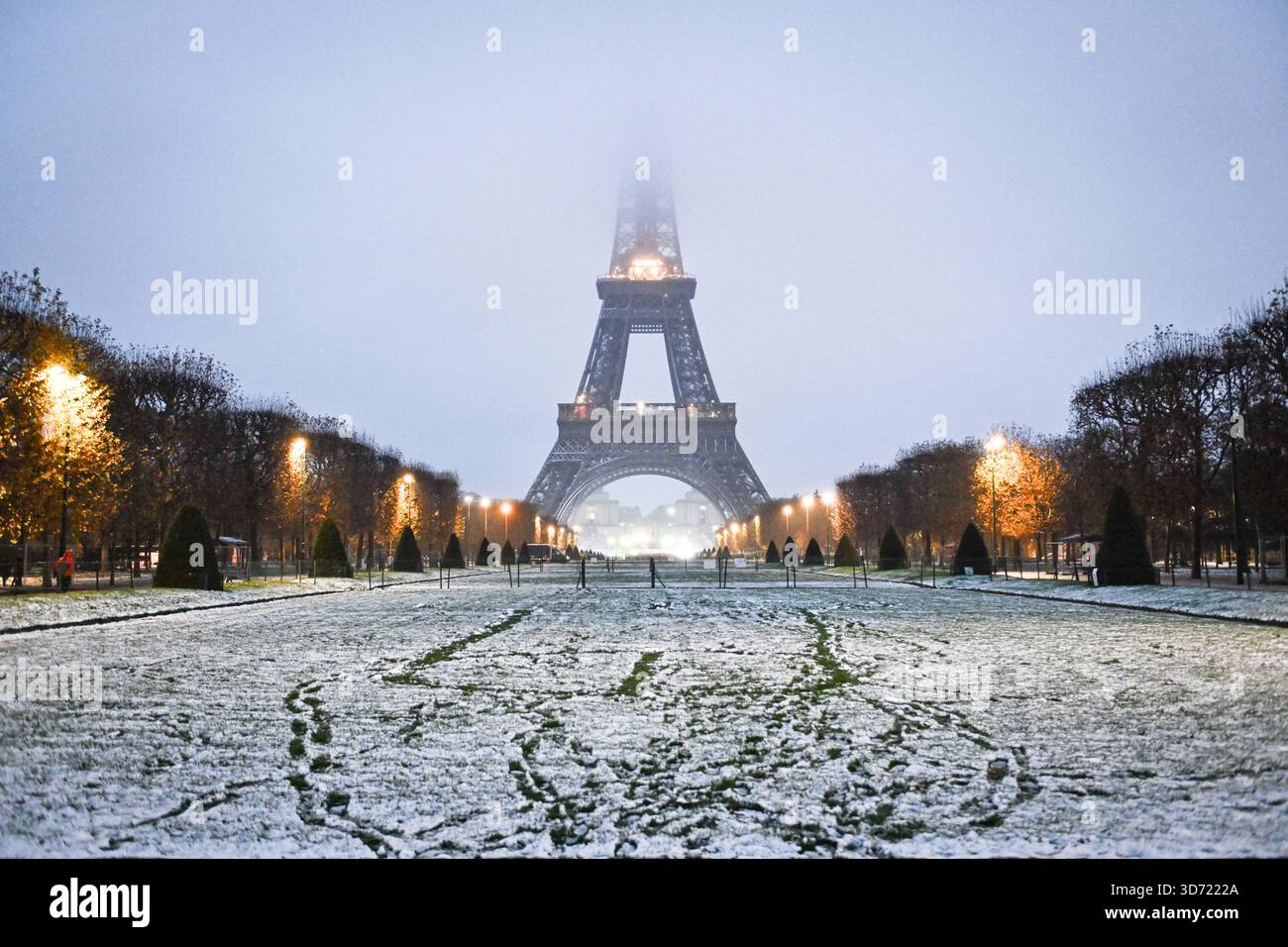 Pedestrians walk around as snow covers the ground around the Eiffel ...