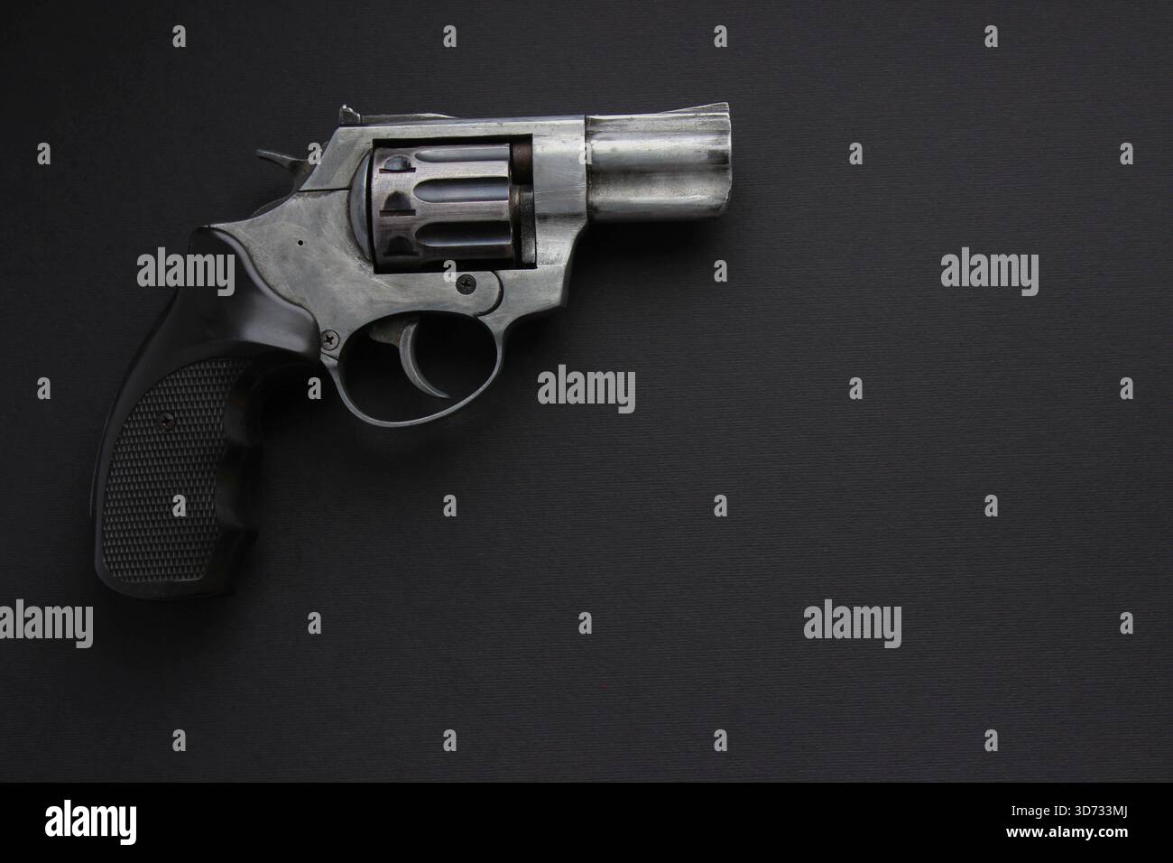Compact steel revolver placed to the left on black background, large ...