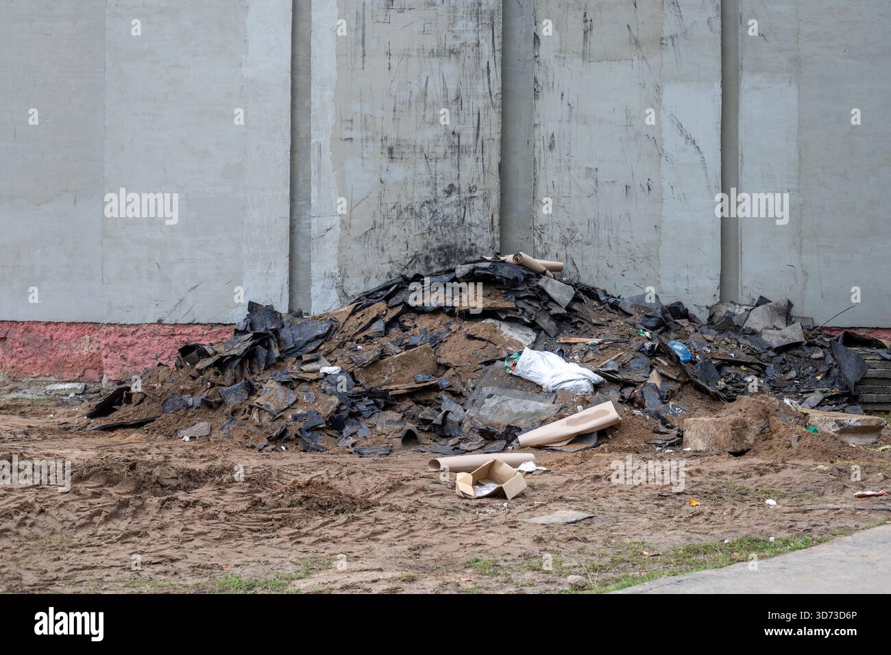 Roofing felt pile, sand and other construction waste against the wall ...