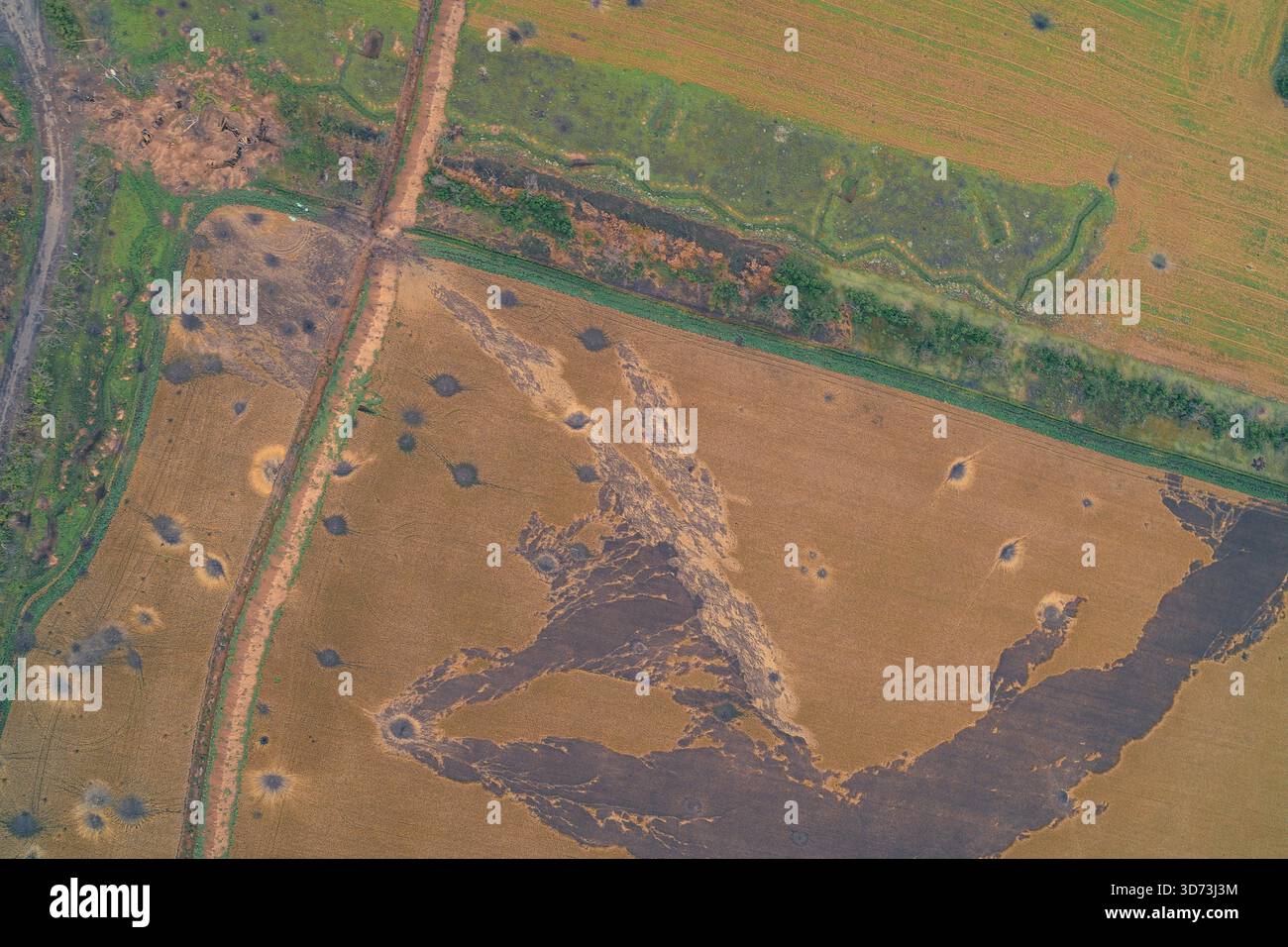 High-angle aerial view of a heavily damaged field with multiple shell ...