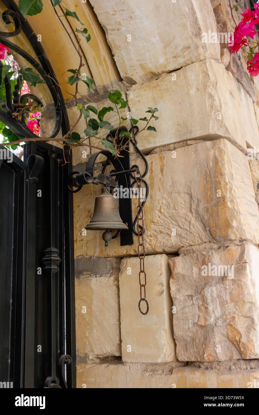 Antique Bell Hanging by Stone Wall and Iron Gate With Vines and Pink ...