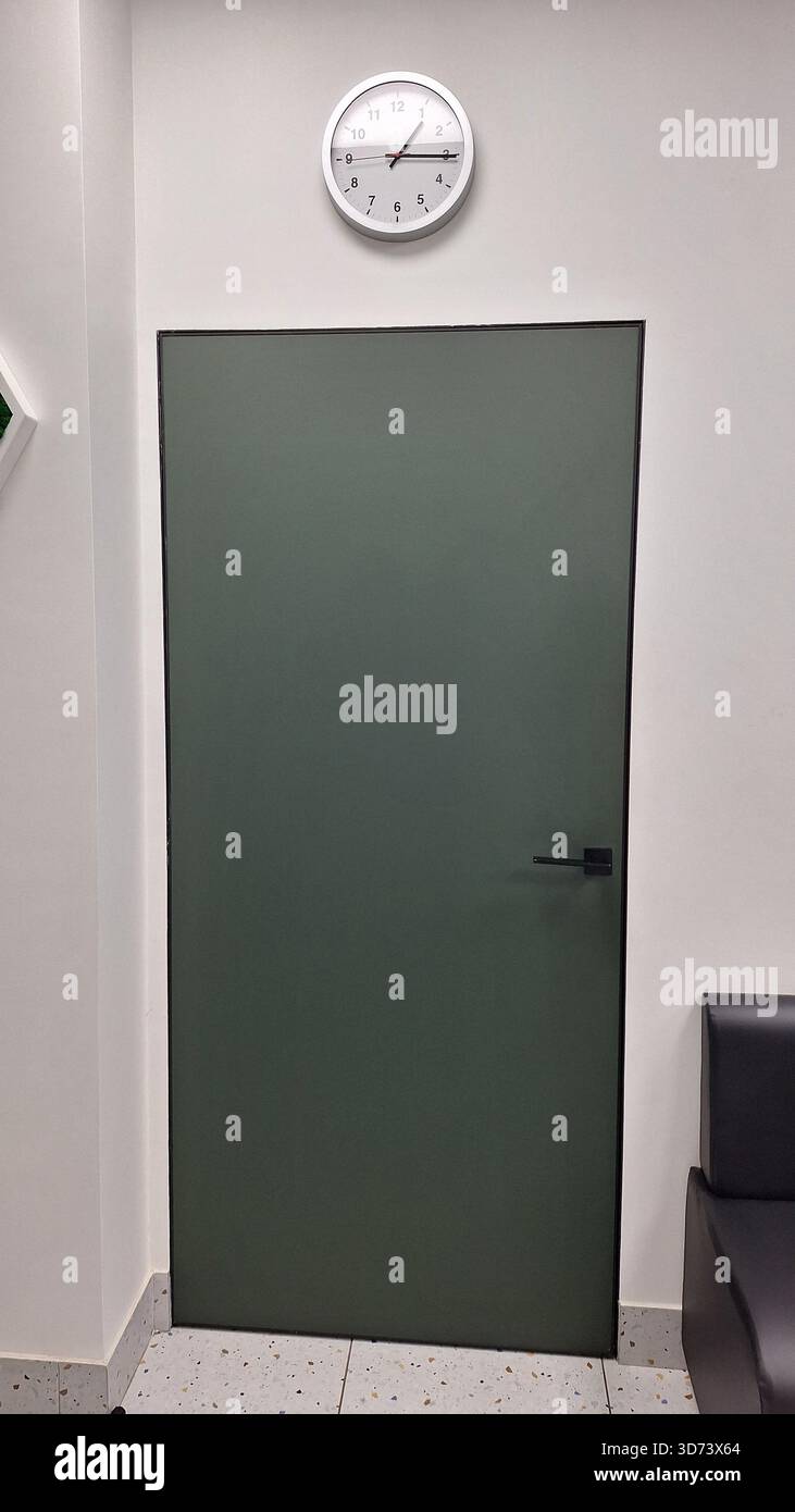 Green door under wall clock in minimalist white room interior Stock ...