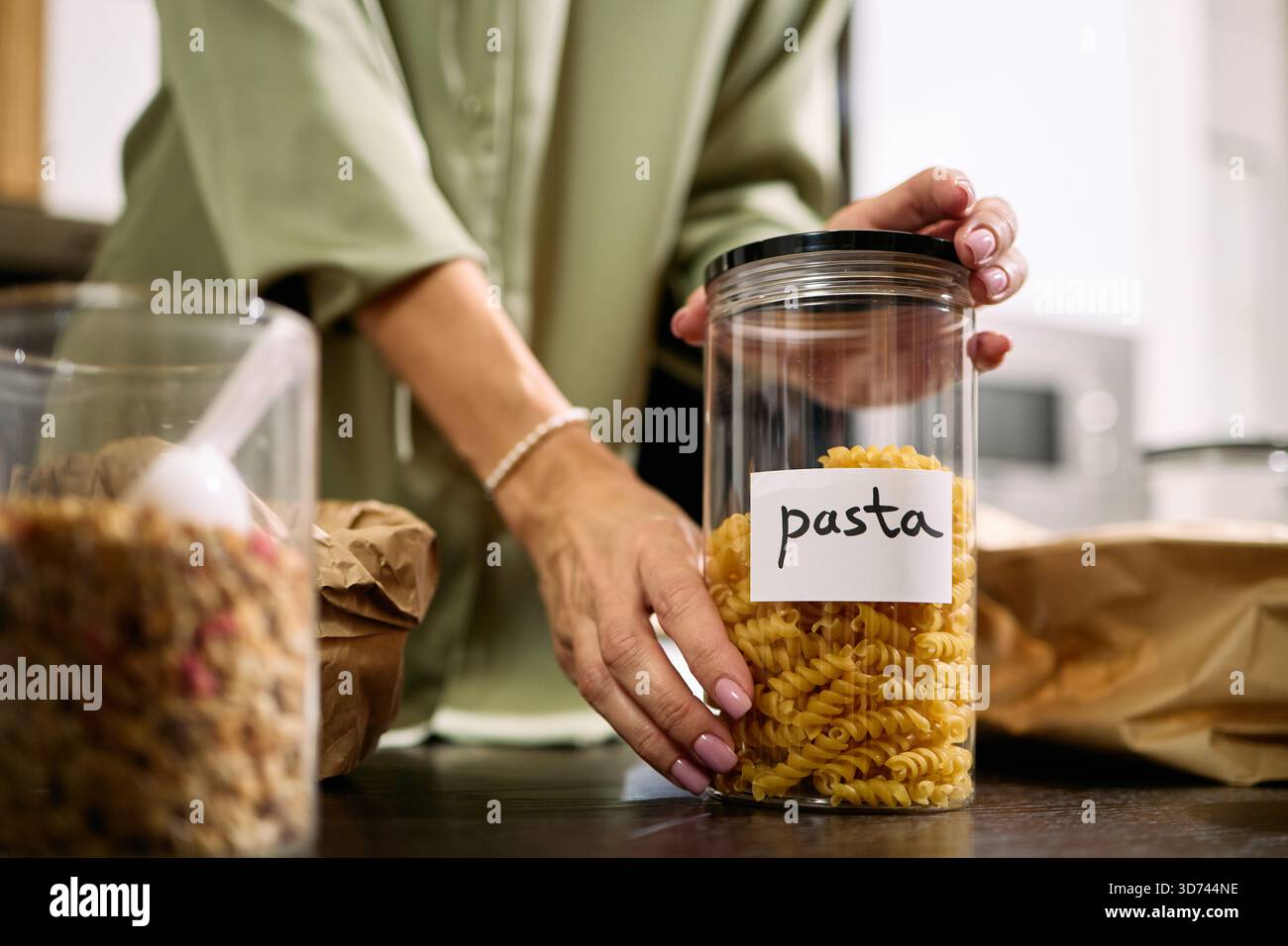 Caucasian young adult woman organizing kitchen pantry, placing ...