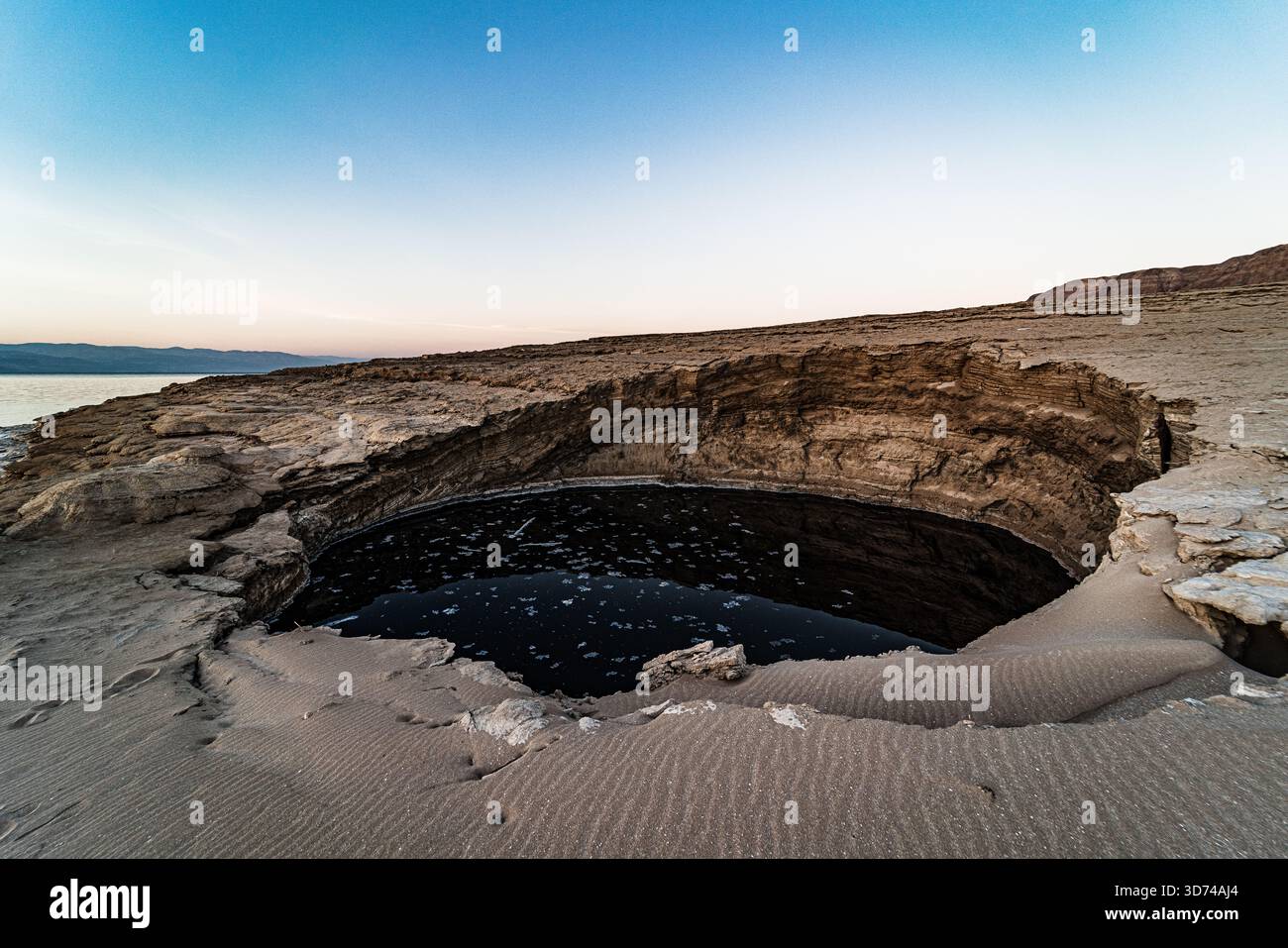 Unique Dead Sea sinkhole with dark black water surrounded by the salt ...