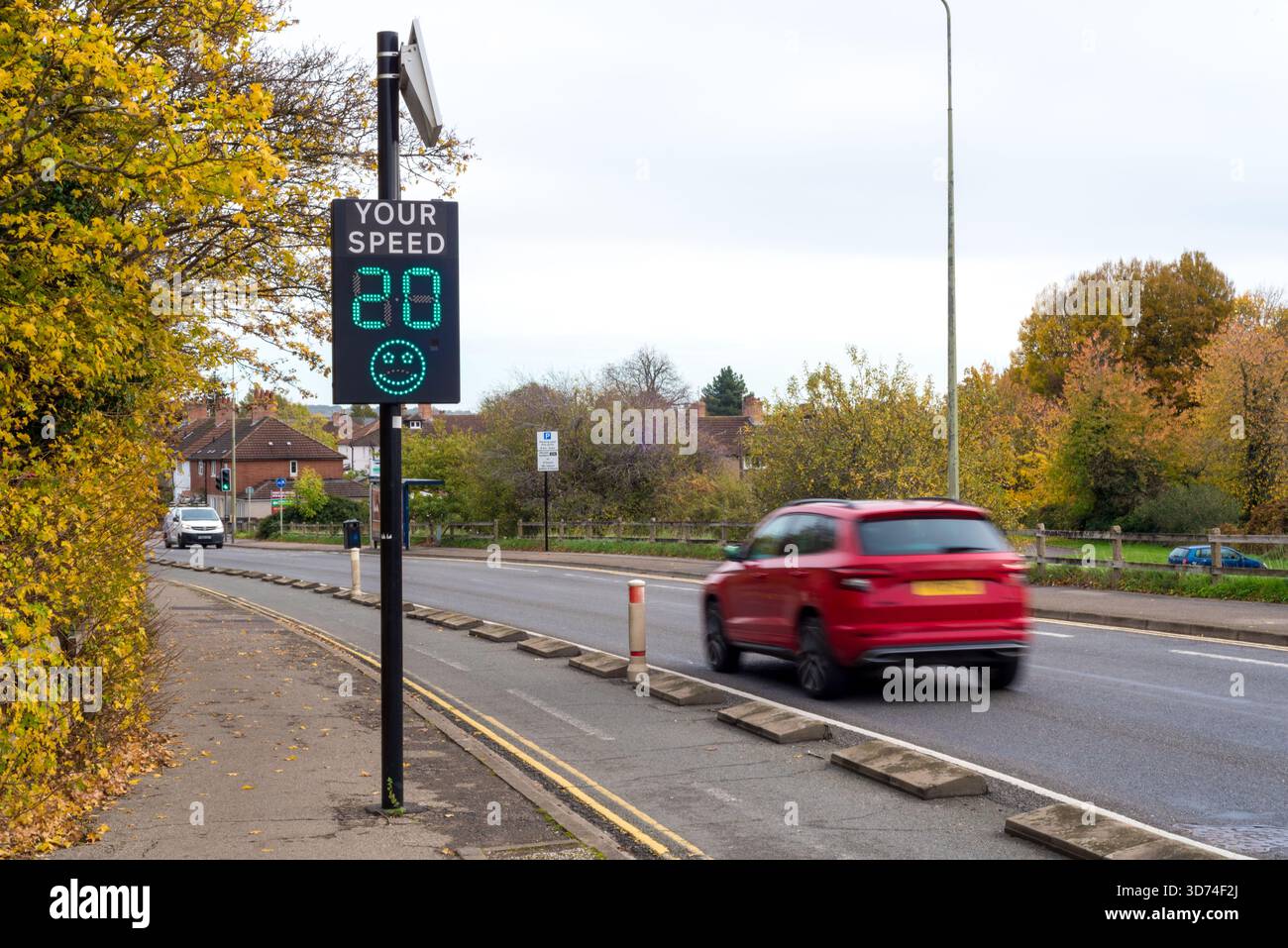 Red car driving past a speed awareness sign on uk road Stock Photo - Alamy