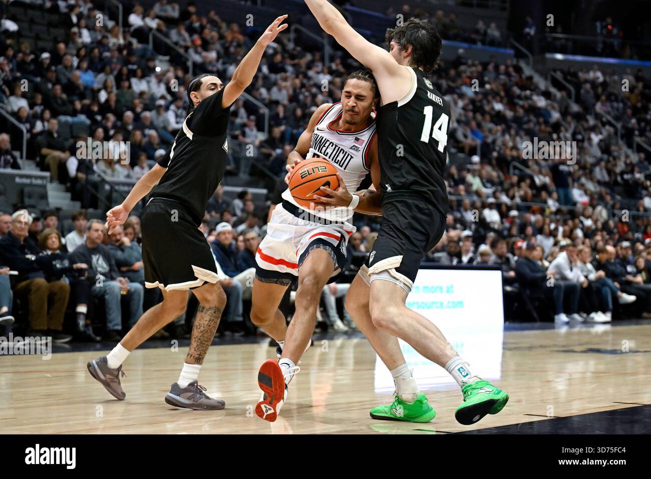 UConn forward Jayden Ross, center, splits the defense of Bryant guard ...