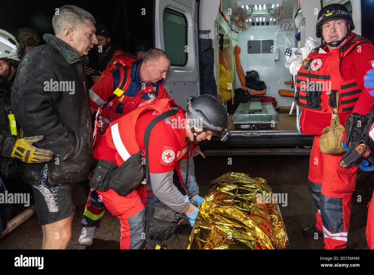 Rescue workers carry a dead body from a residential building damaged by ...