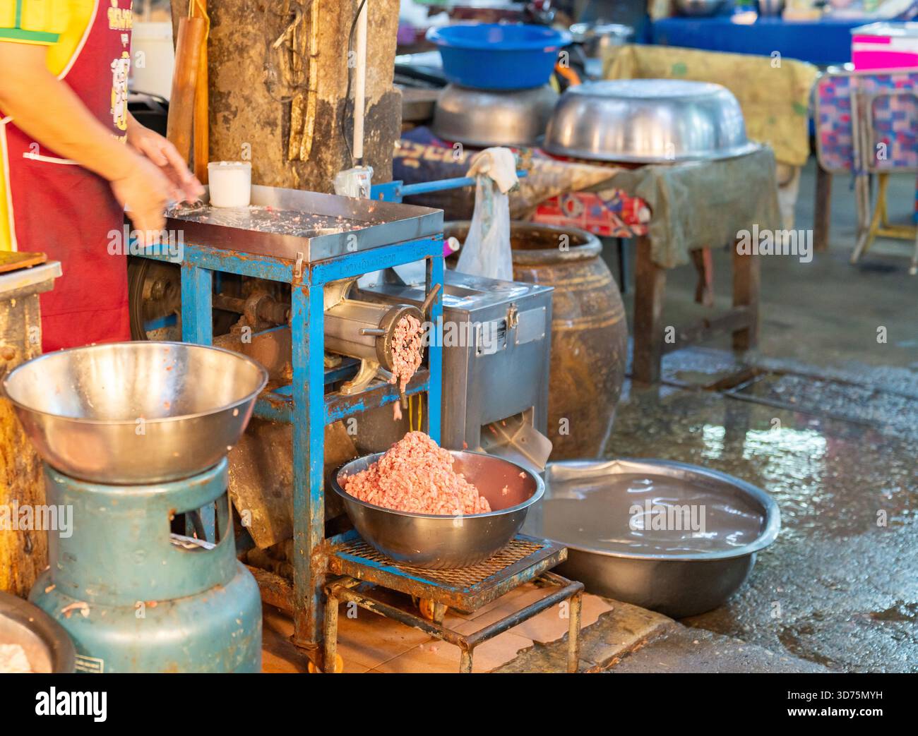 The focal point is a blue metal meat grinding machine actively ...