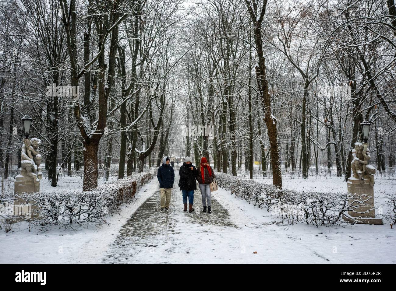 Varsovians walk through the snow are looked over by two statues of ...
