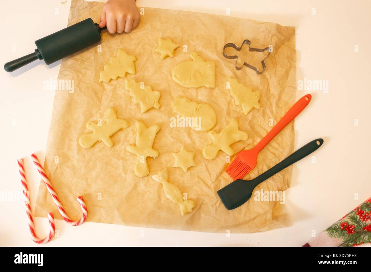 Cutting and shaping holiday cookies on a kitchen counter with various ...