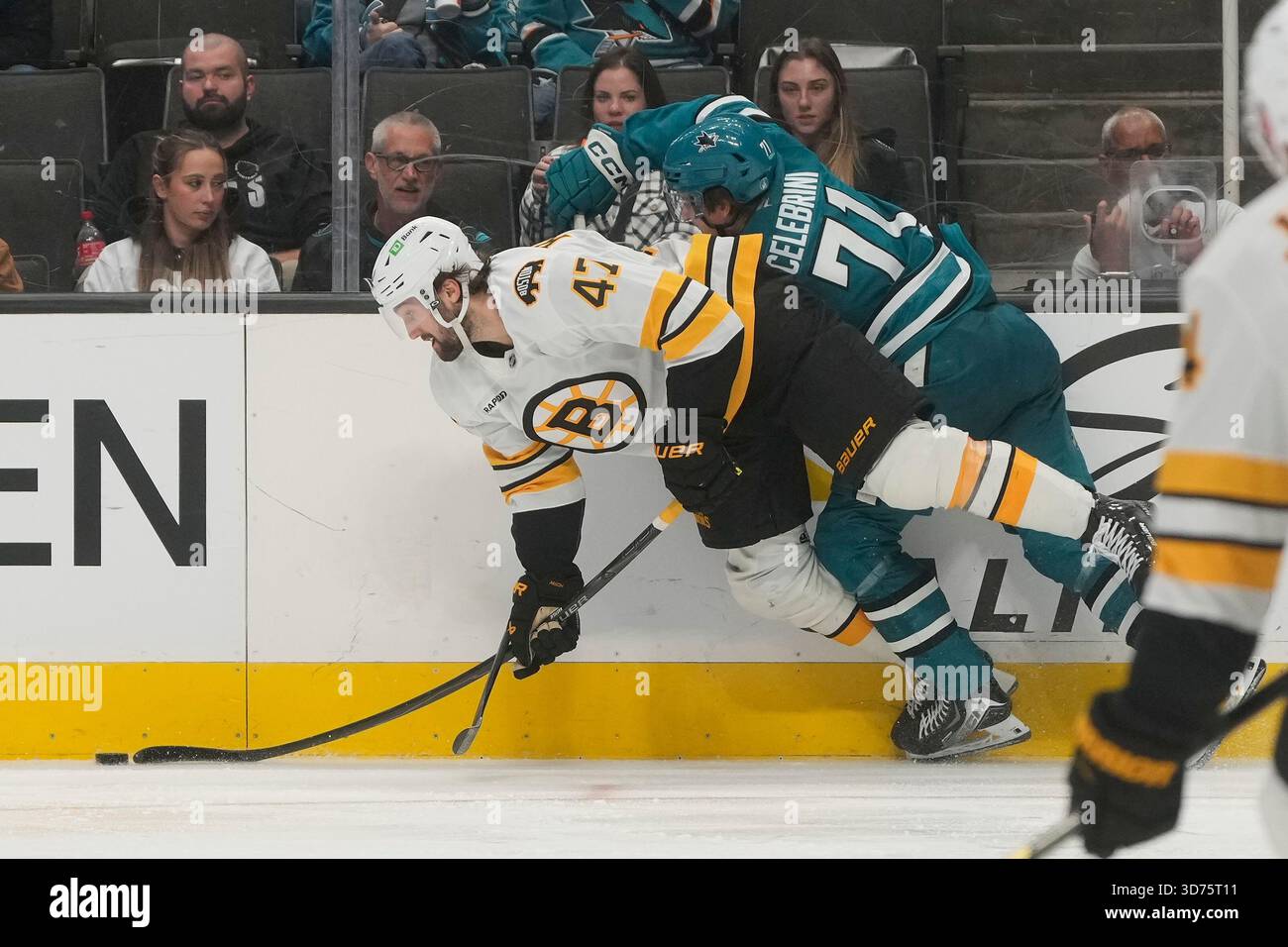 Boston Bruins center Mark Kastelic (47) reaches for the puck in front of San Jose Sharks center ...