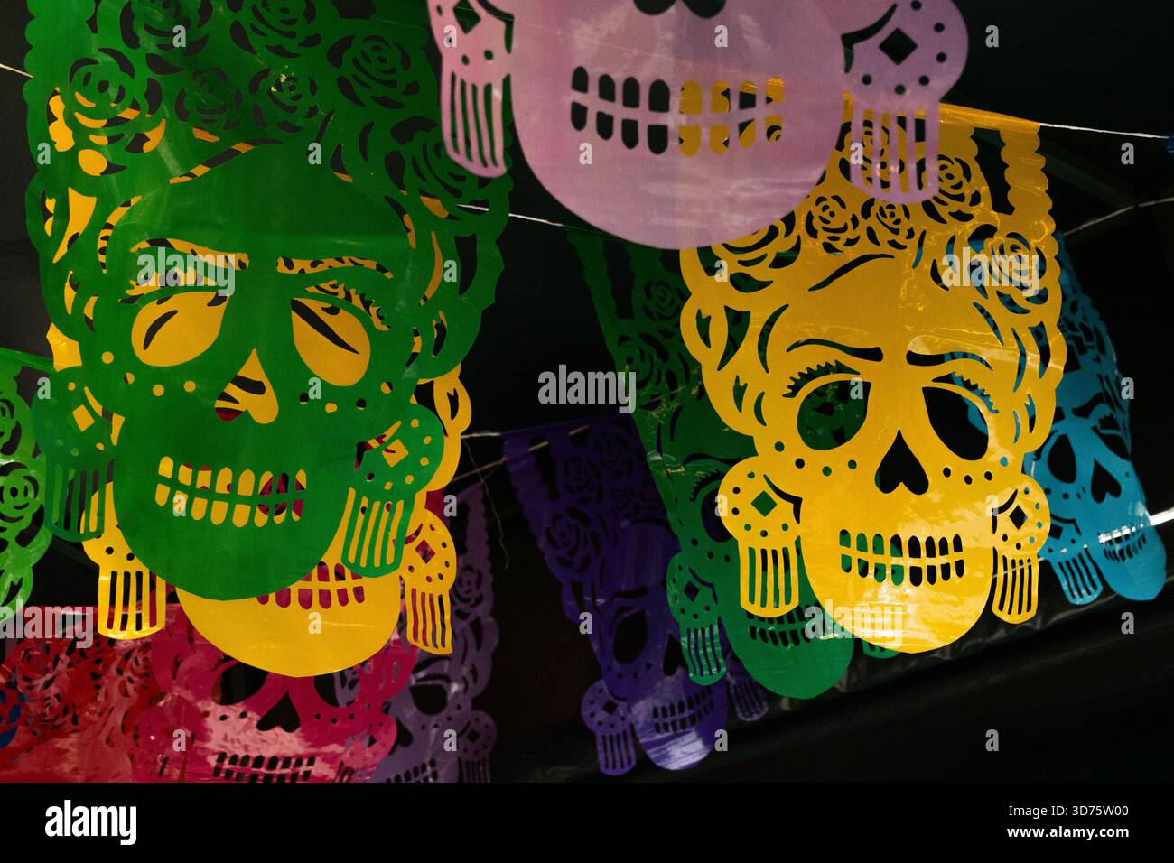 A colorful display of paper skulls and flowers. The skulls are in ...