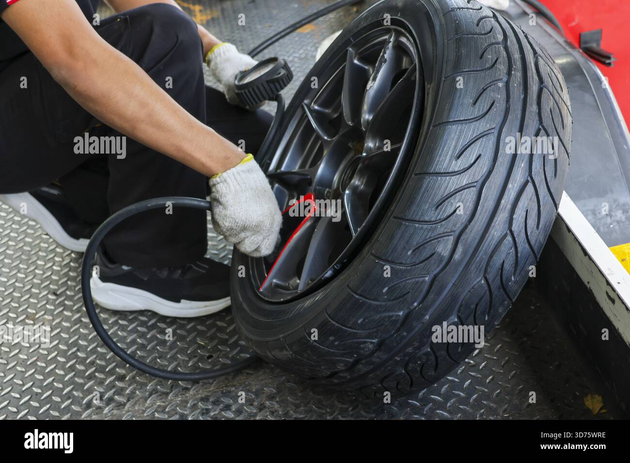 Focused mechanic inflating car tire on an alloy wheel in garage ...