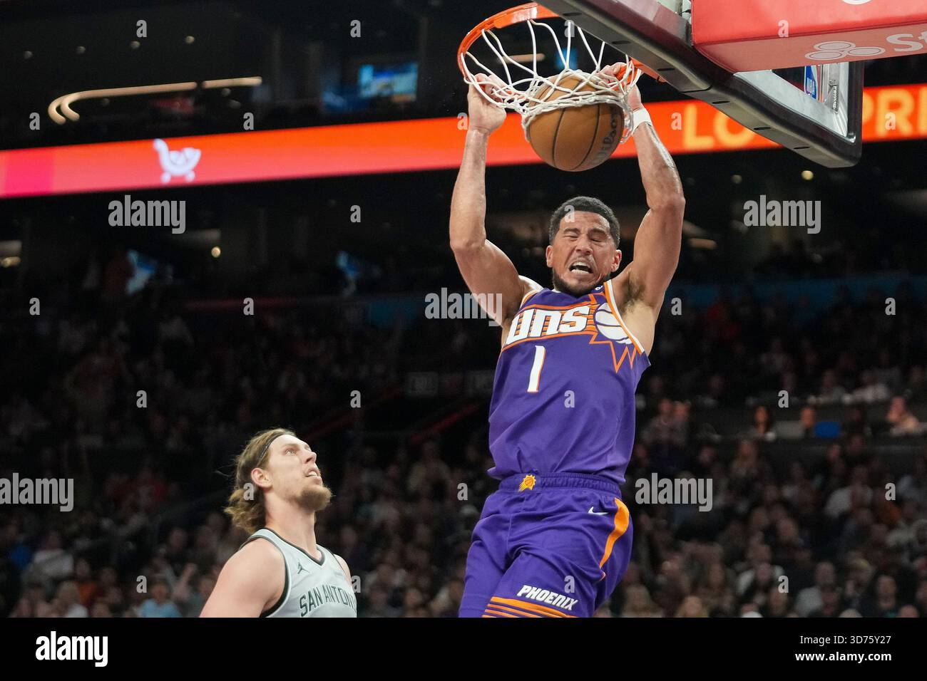 Phoenix Suns guard Devin Booker, right, dunks as San Antonio Spurs forward Kelly Olynyk looks on ...