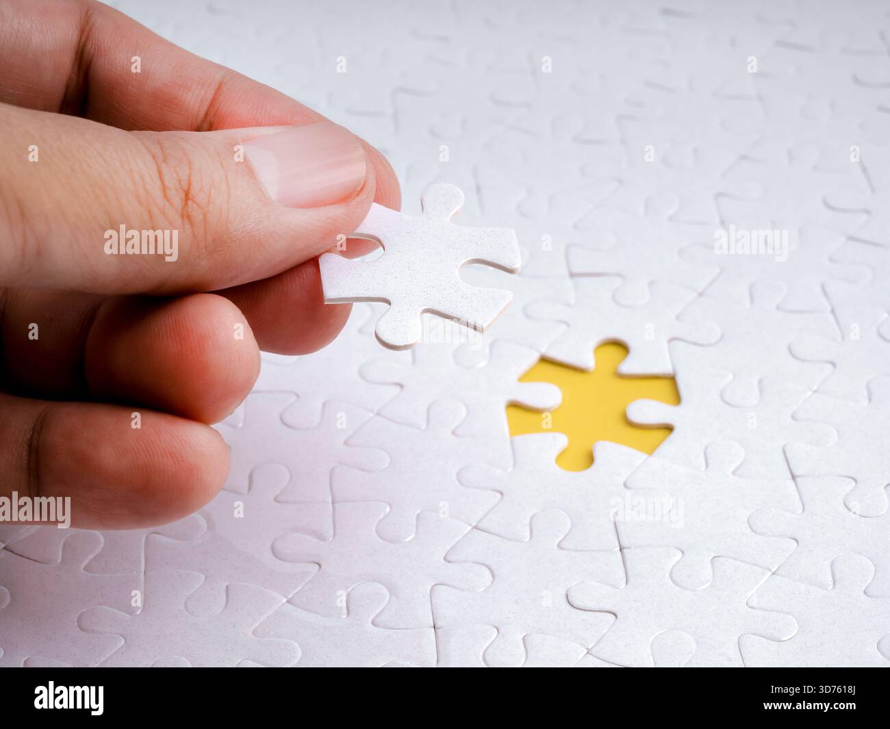 Close-up hand placing final puzzle piece into missing spot on white ...