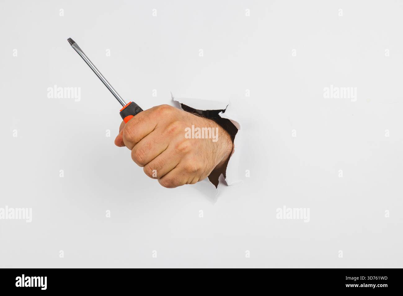 A hand is reaching through a torn section of a white wall, gripping a ...