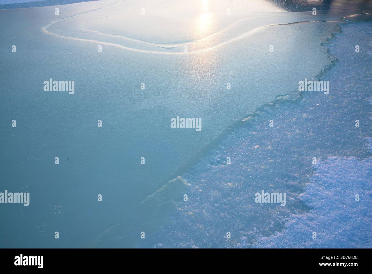 Golden sunlight reflection on frozen winter lake surface creating calm ...