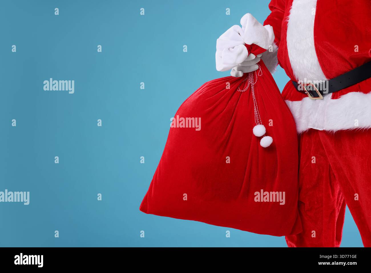 Santa Claus holding sack on light blue background, closeup with space ...