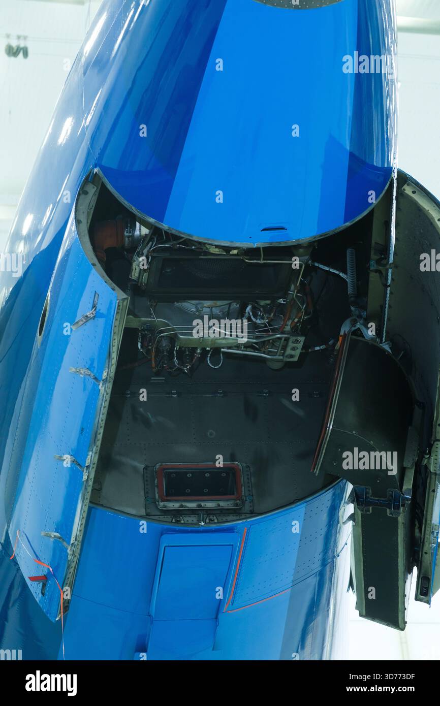 A blue airplane fuselage has its maintenance hatch open, exposing ...