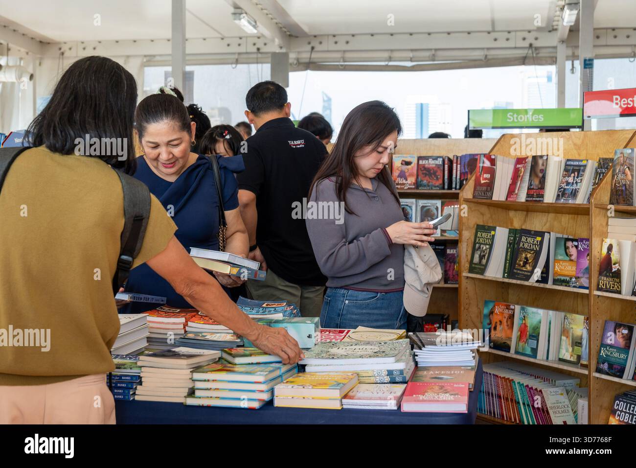 Women browsing books, with one checking her phone at the Doulos Hope ...