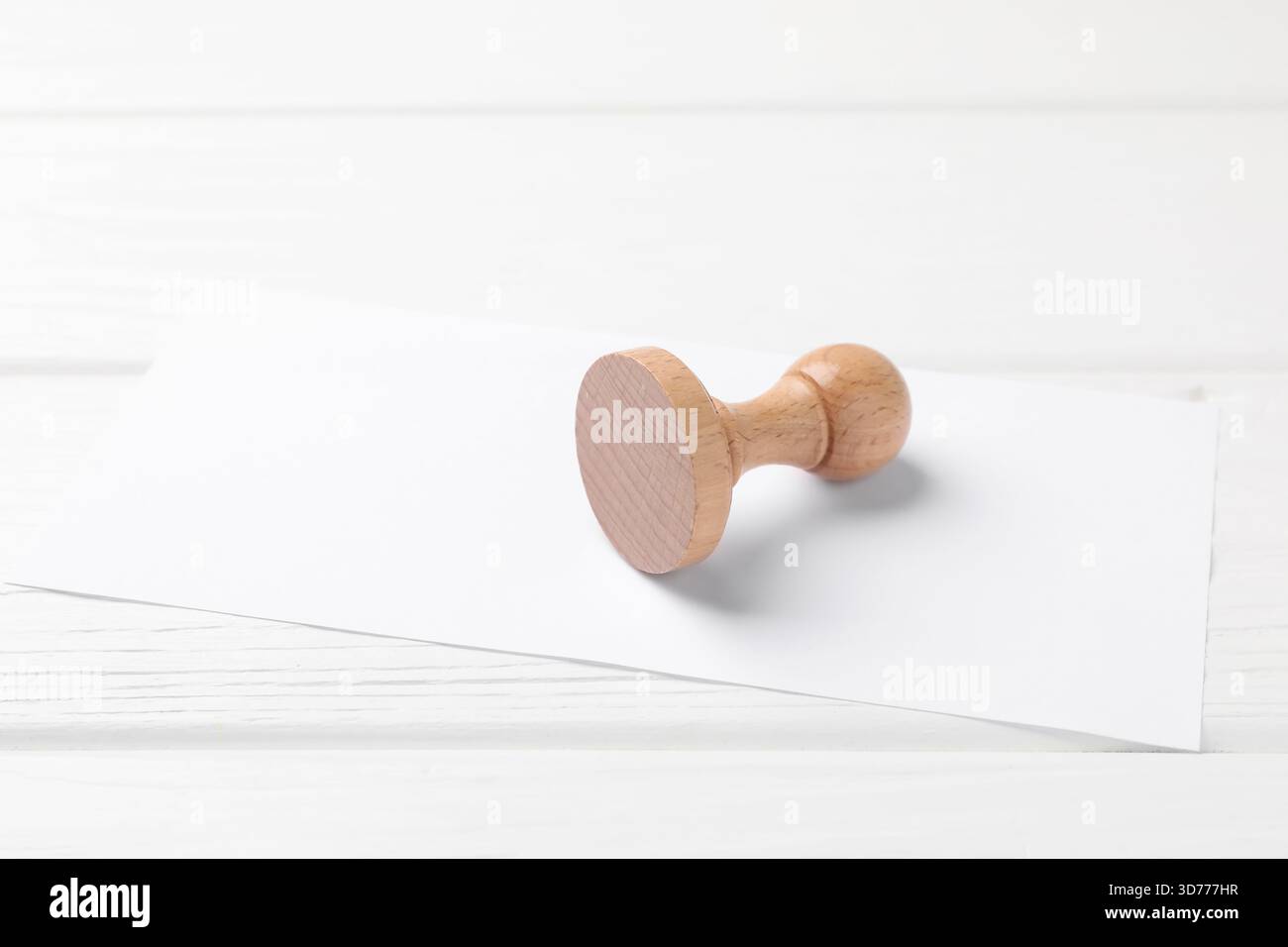 One wooden stamp and blank sheet of paper on white table, closeup ...