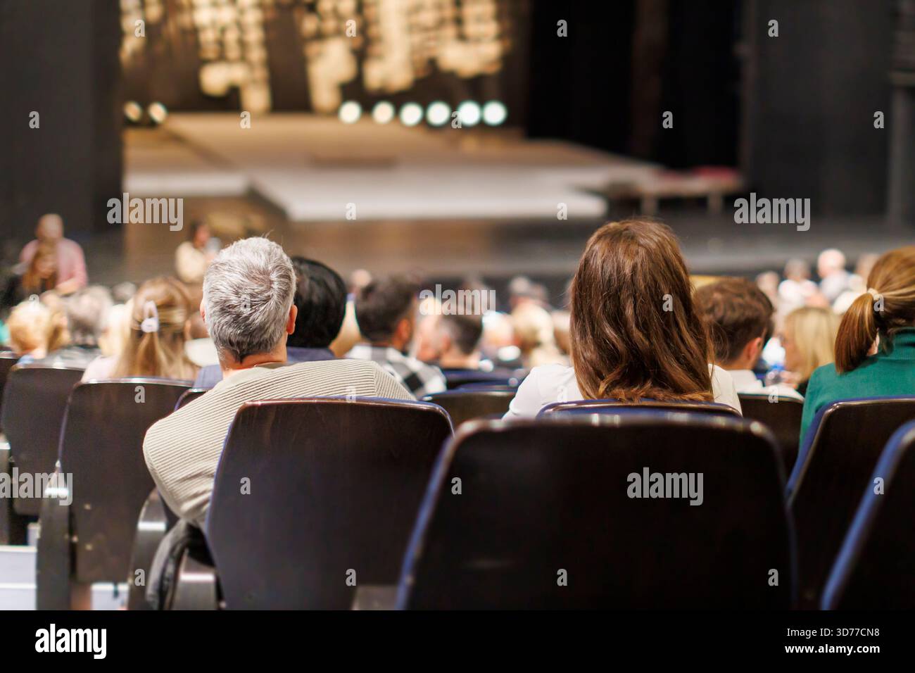 Audience watching a performance in a theater during an evening show ...