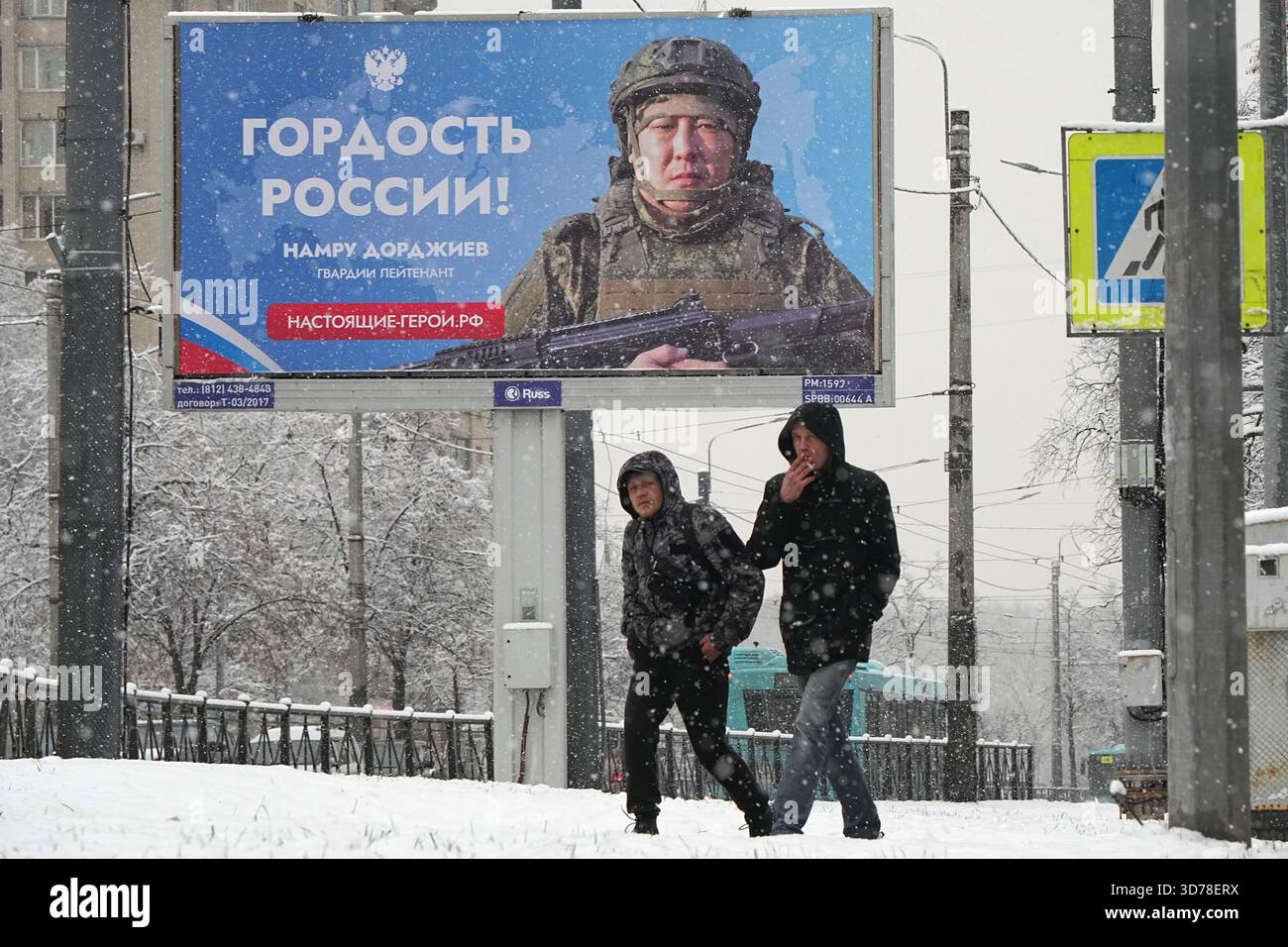 Men walk past a billboard showing a Russian soldier participating in ...